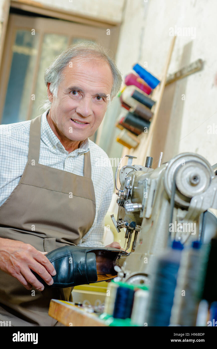 Cobbler holding shoe, stood next to sewing machine Stock Photo - Alamy