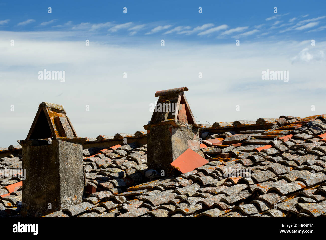 Two old vintage chimneys on old tiled roof in small italian city ...