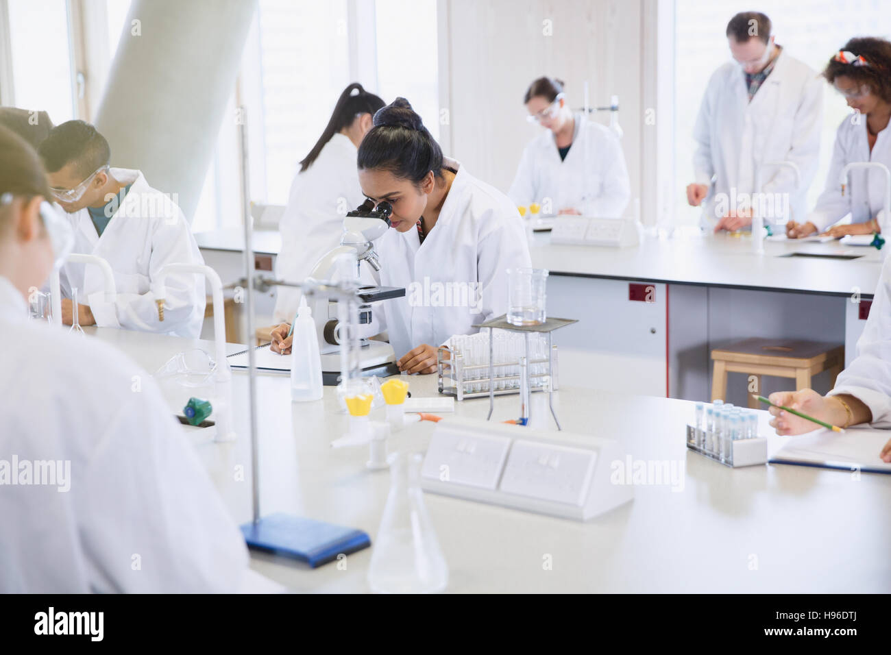 College students using microscope conducting scientific experiment in ...