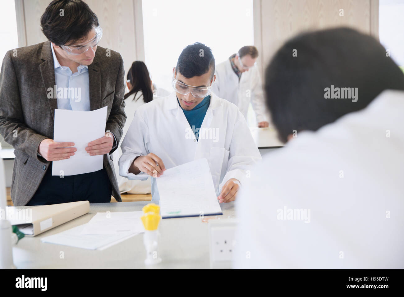 Science professor helping college student in science laboratory ...