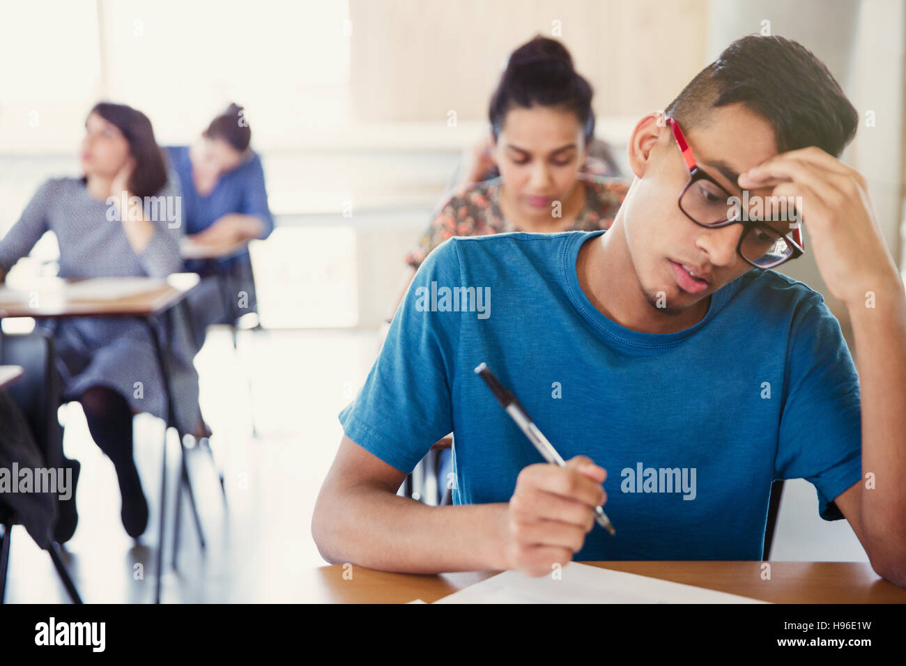 Serious male college student taking test at desk in classroom Stock ...
