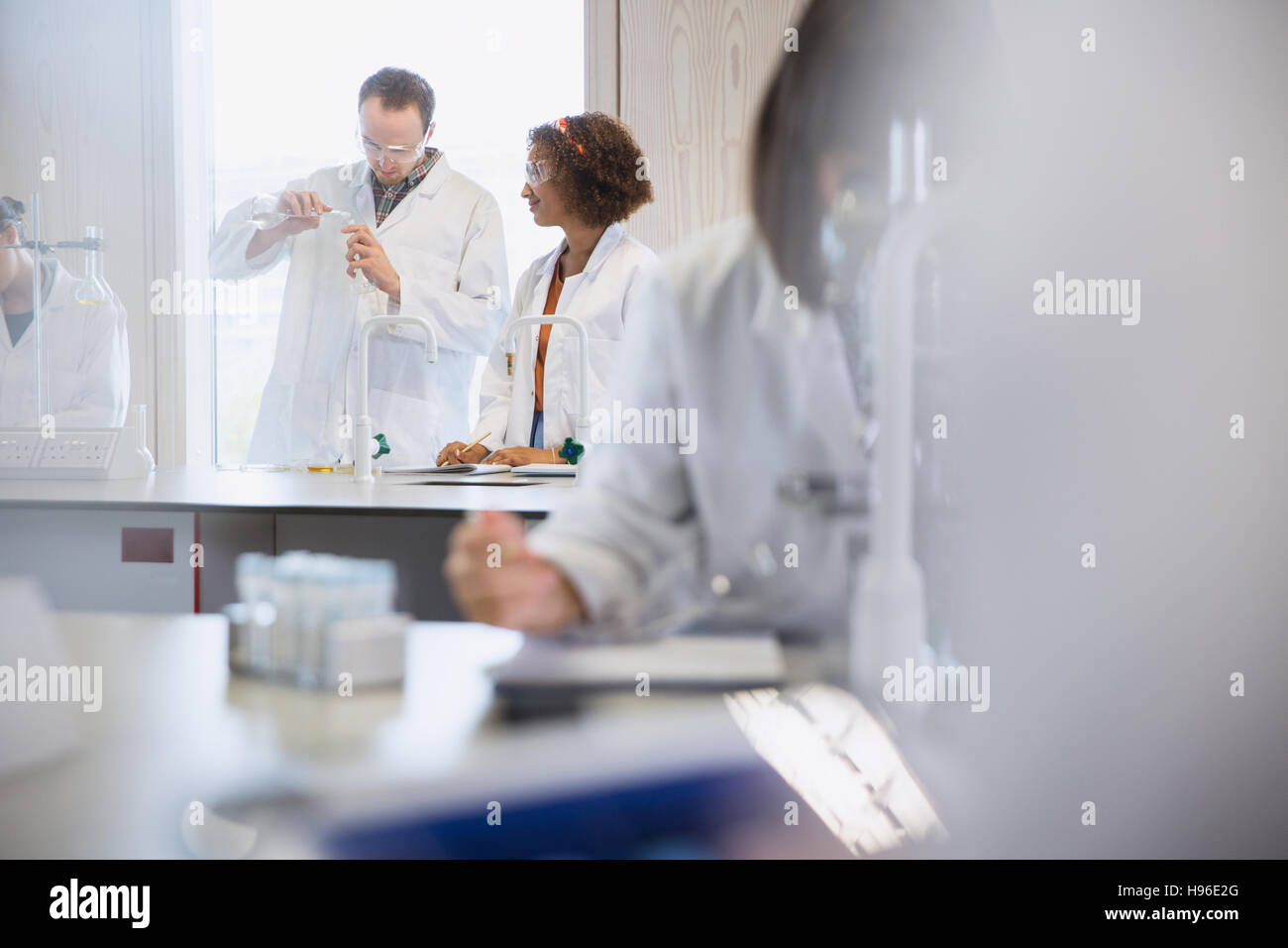College students conducting scientific experiment in science laboratory ...