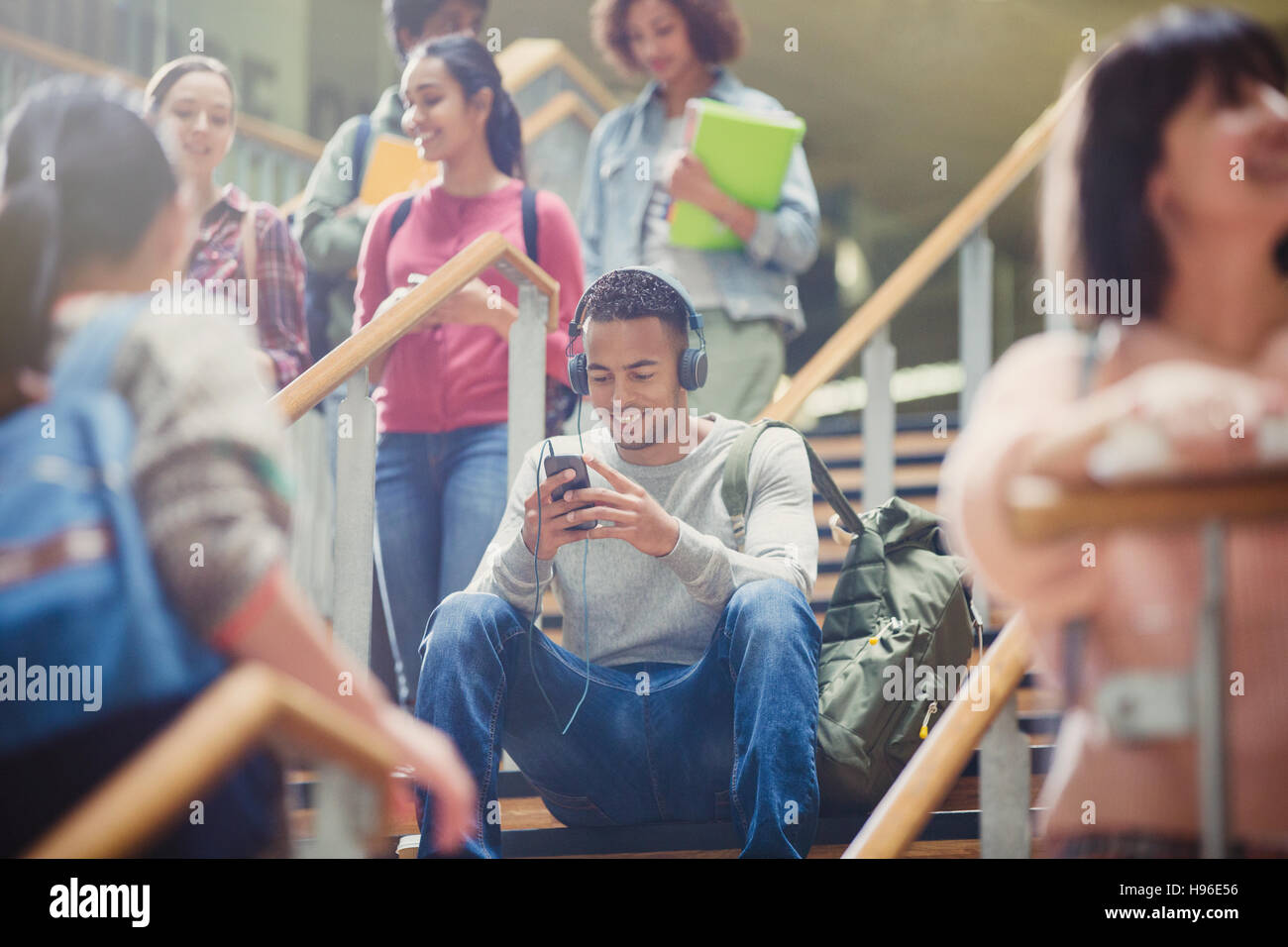 Male college student listening to mp3 player in busy stairway Stock ...