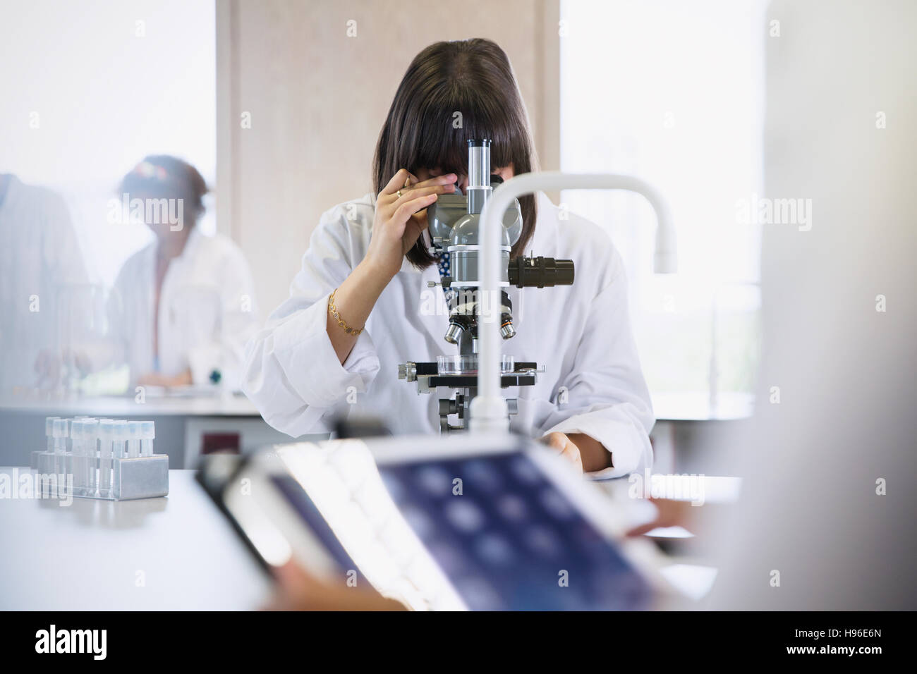 Female college student using microscope in science laboratory classroom ...