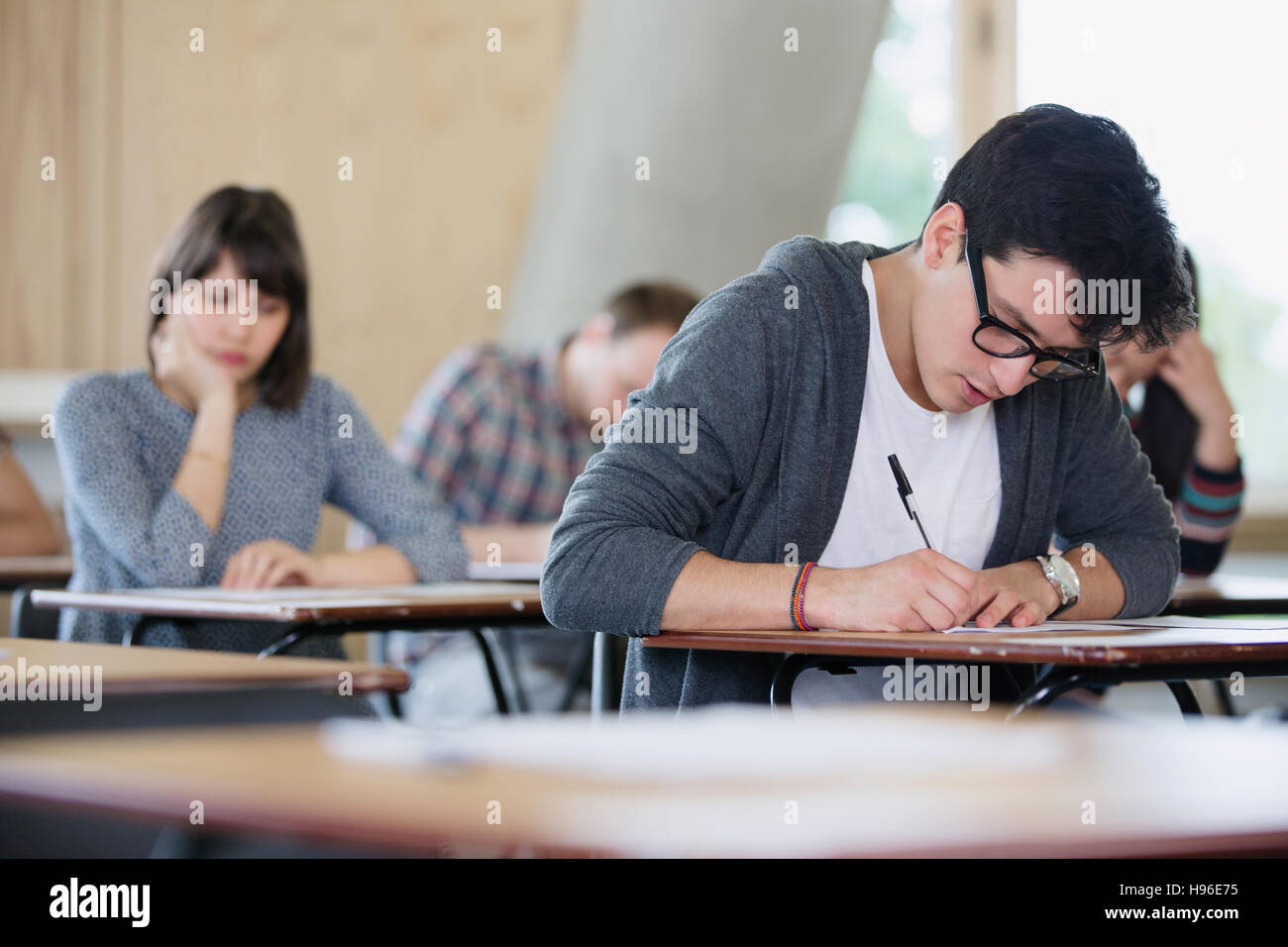 Focused male college student taking test at desk in classroom Stock ...