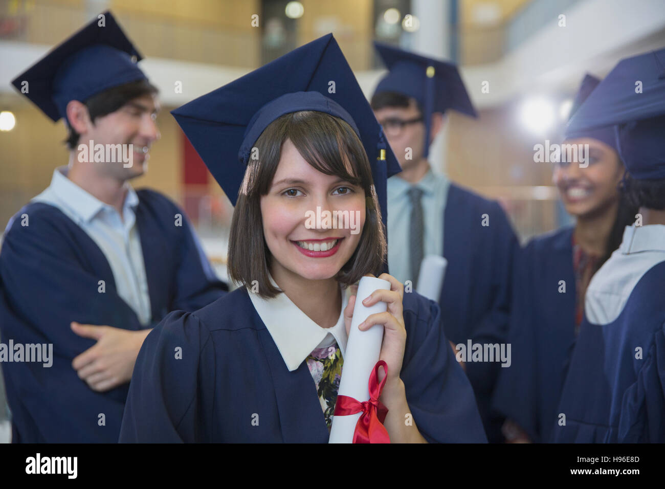 Portrait smiling female college graduate in cap and gown holding ...