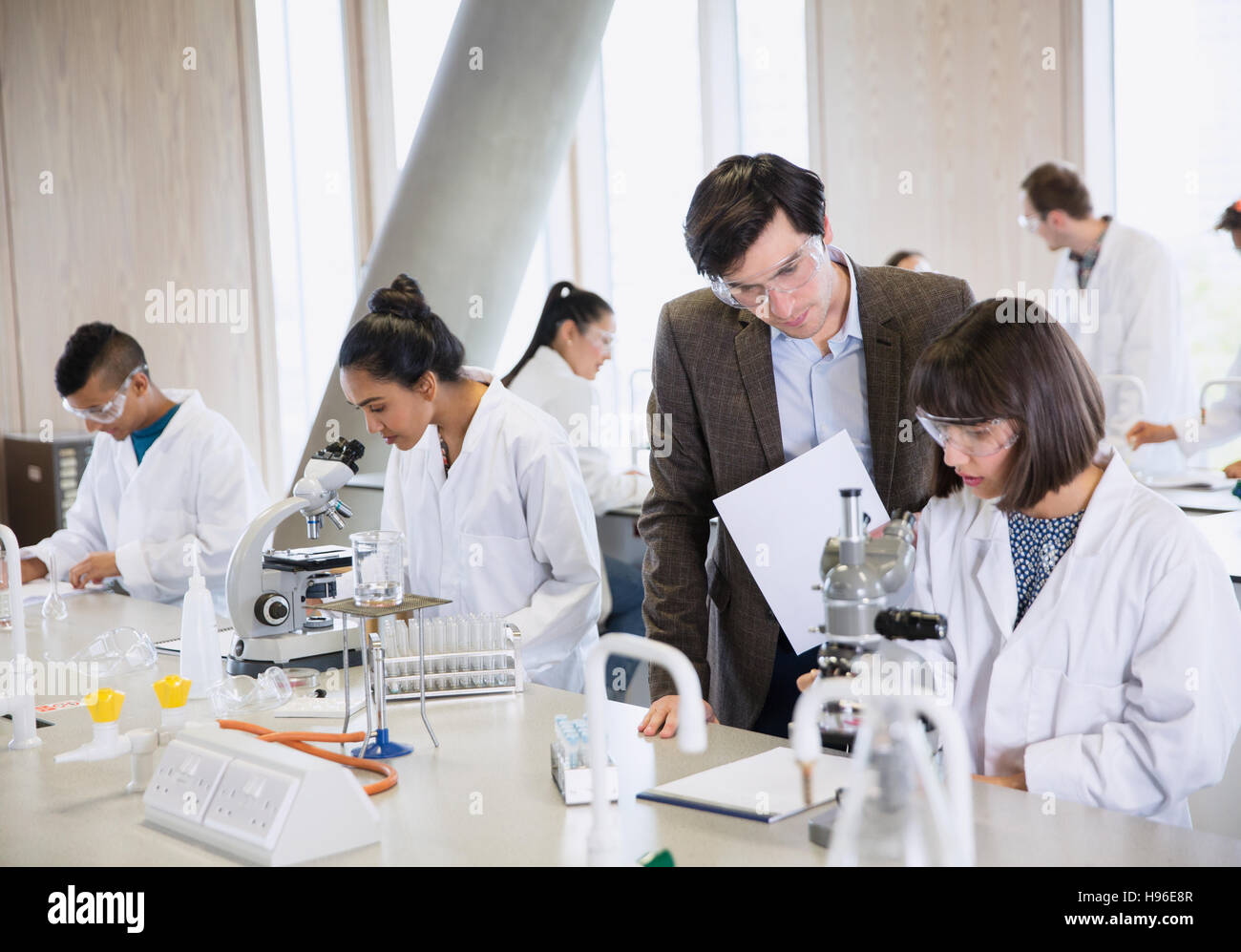 Science professor helping college student conducting scientific ...