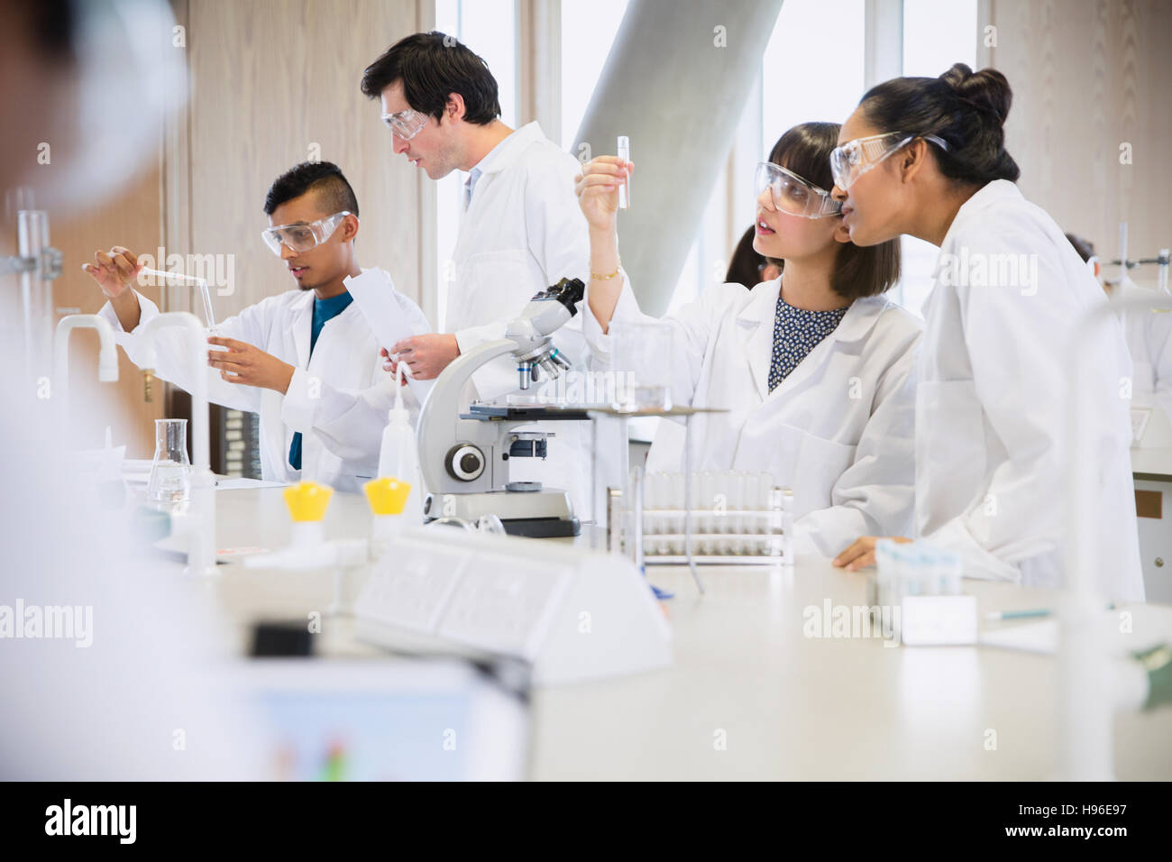 College students conducting scientific experiment in science laboratory ...