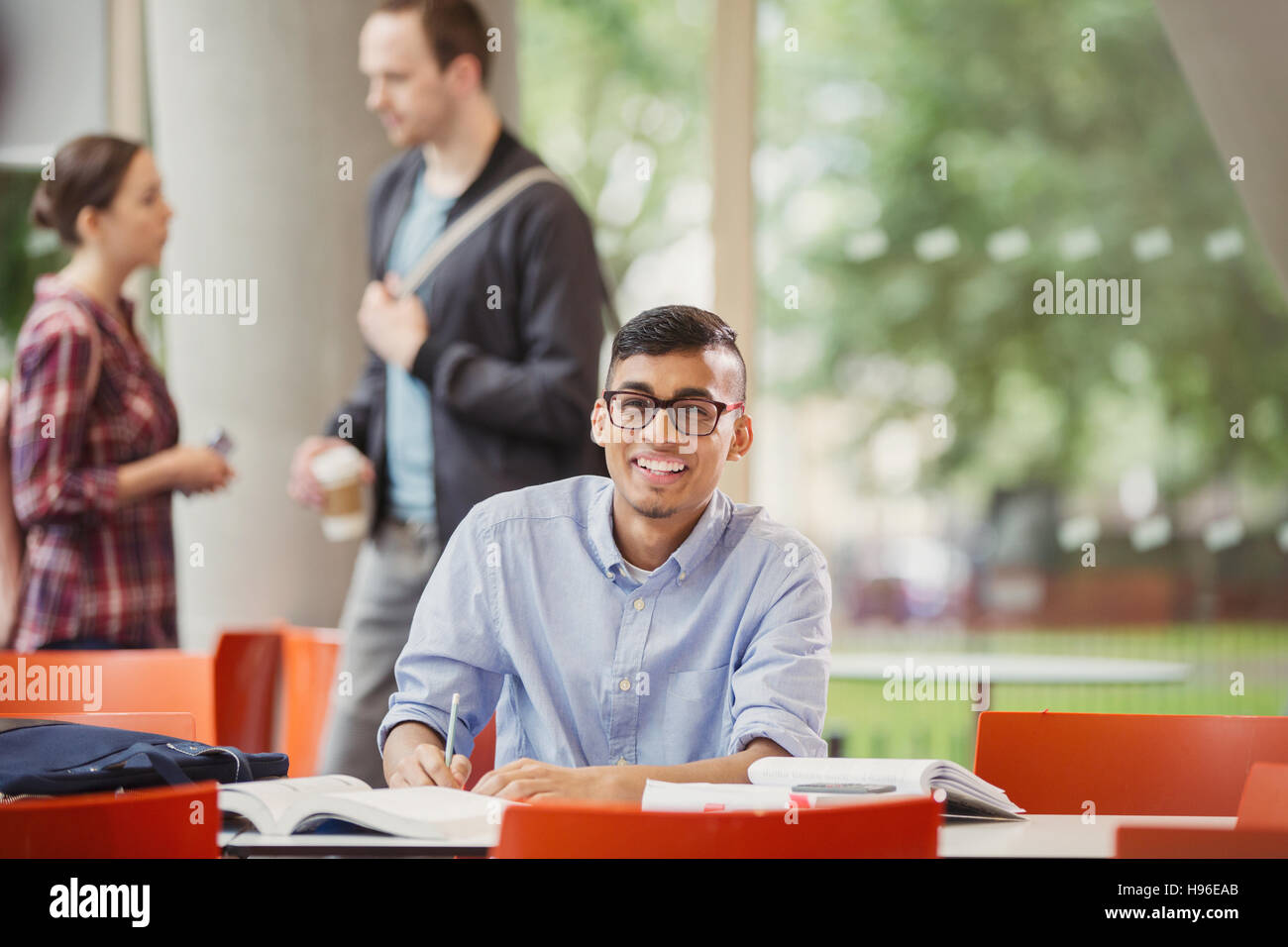 Portrait smiling college student studying at table Stock Photo - Alamy