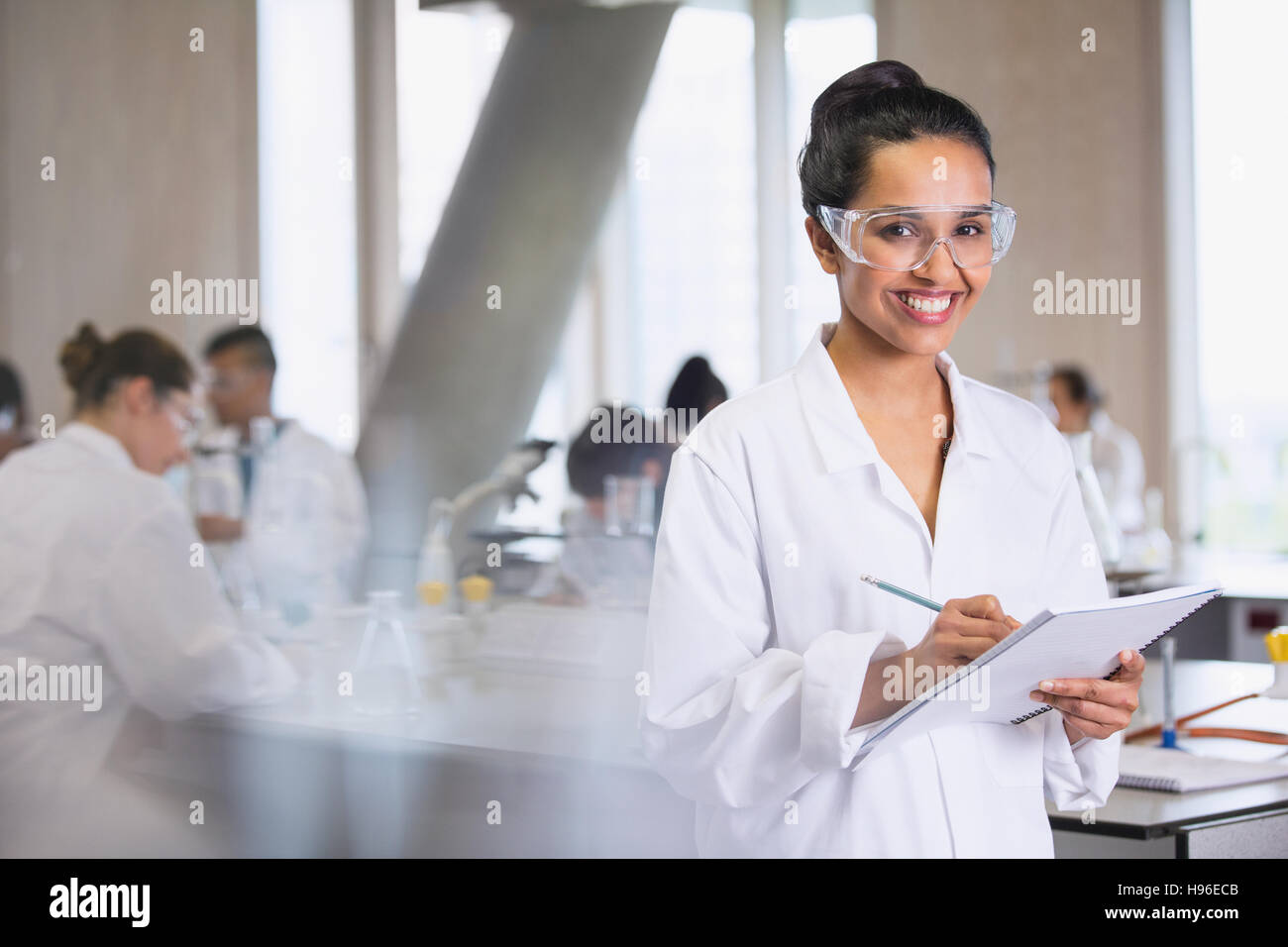 Portrait smiling female college student taking notes in science ...