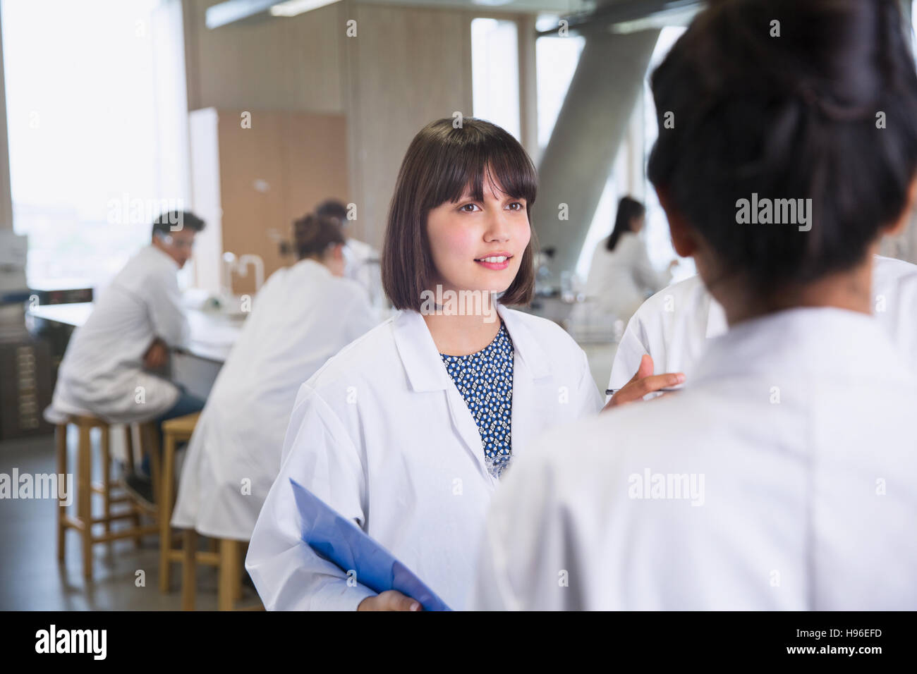 Female college students in lab coats talking in science laboratory ...