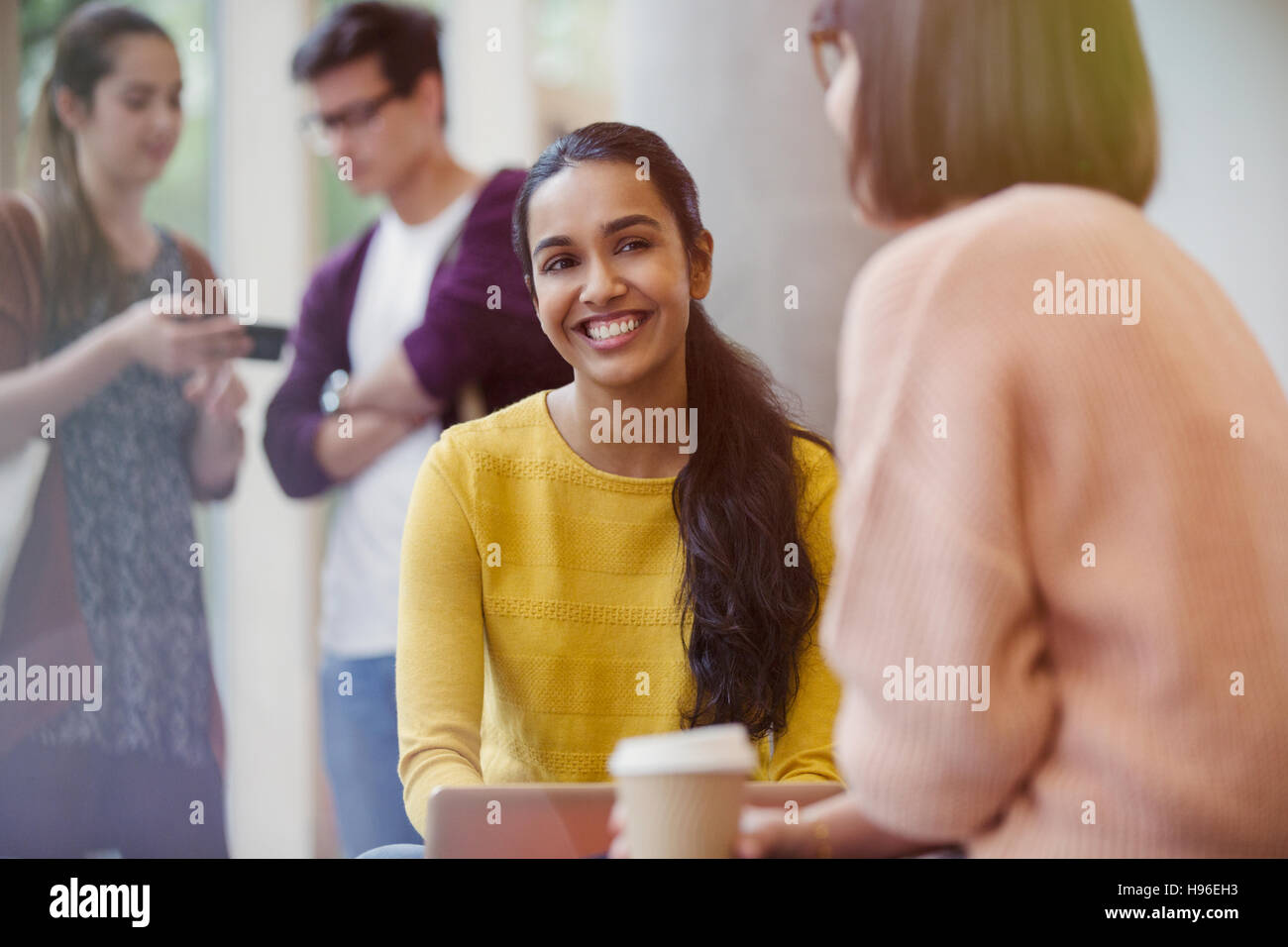 Smiling female college students drinking coffee and talking Stock Photo ...