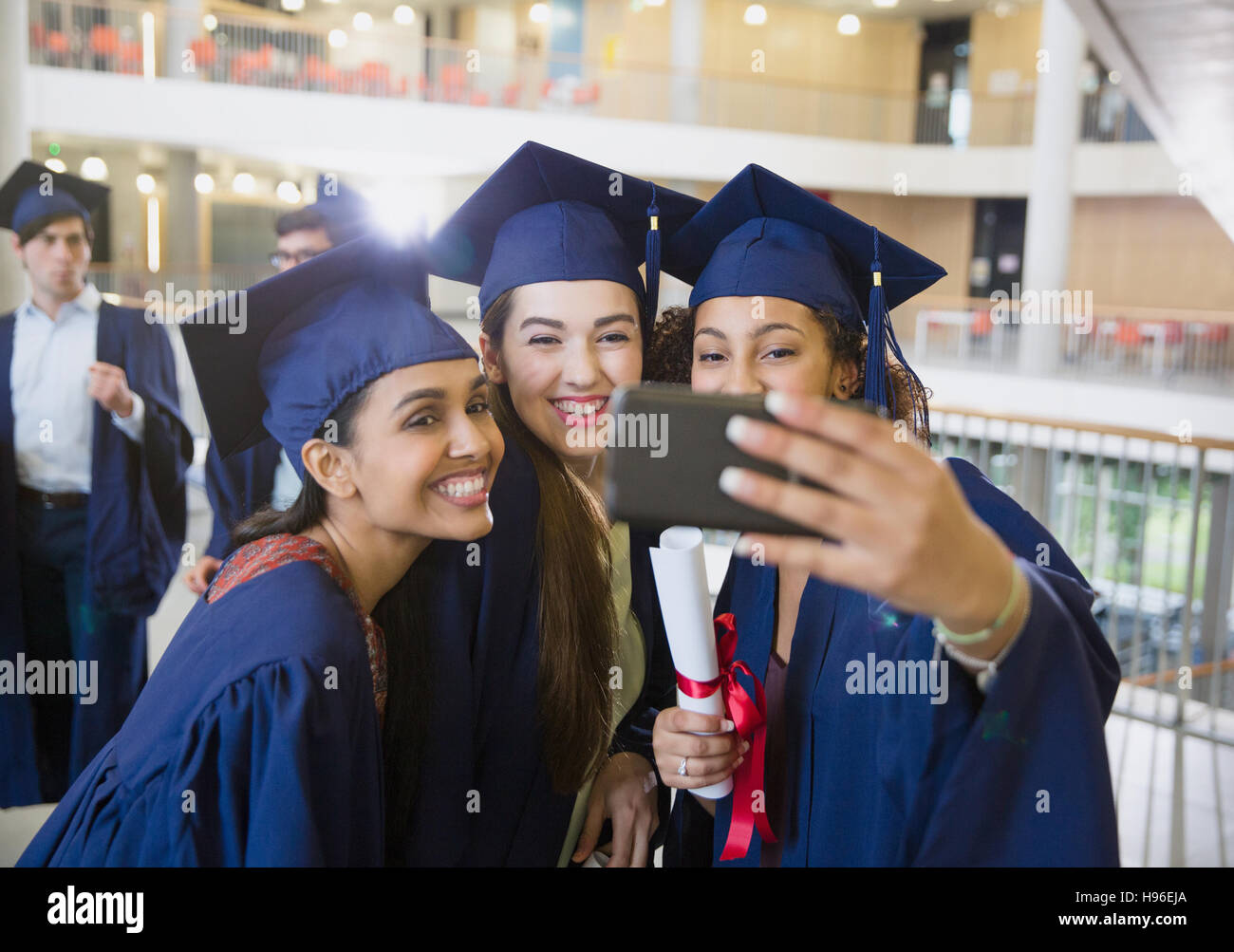 Female college graduates in cap and gown taking selfie Stock Photo - Alamy