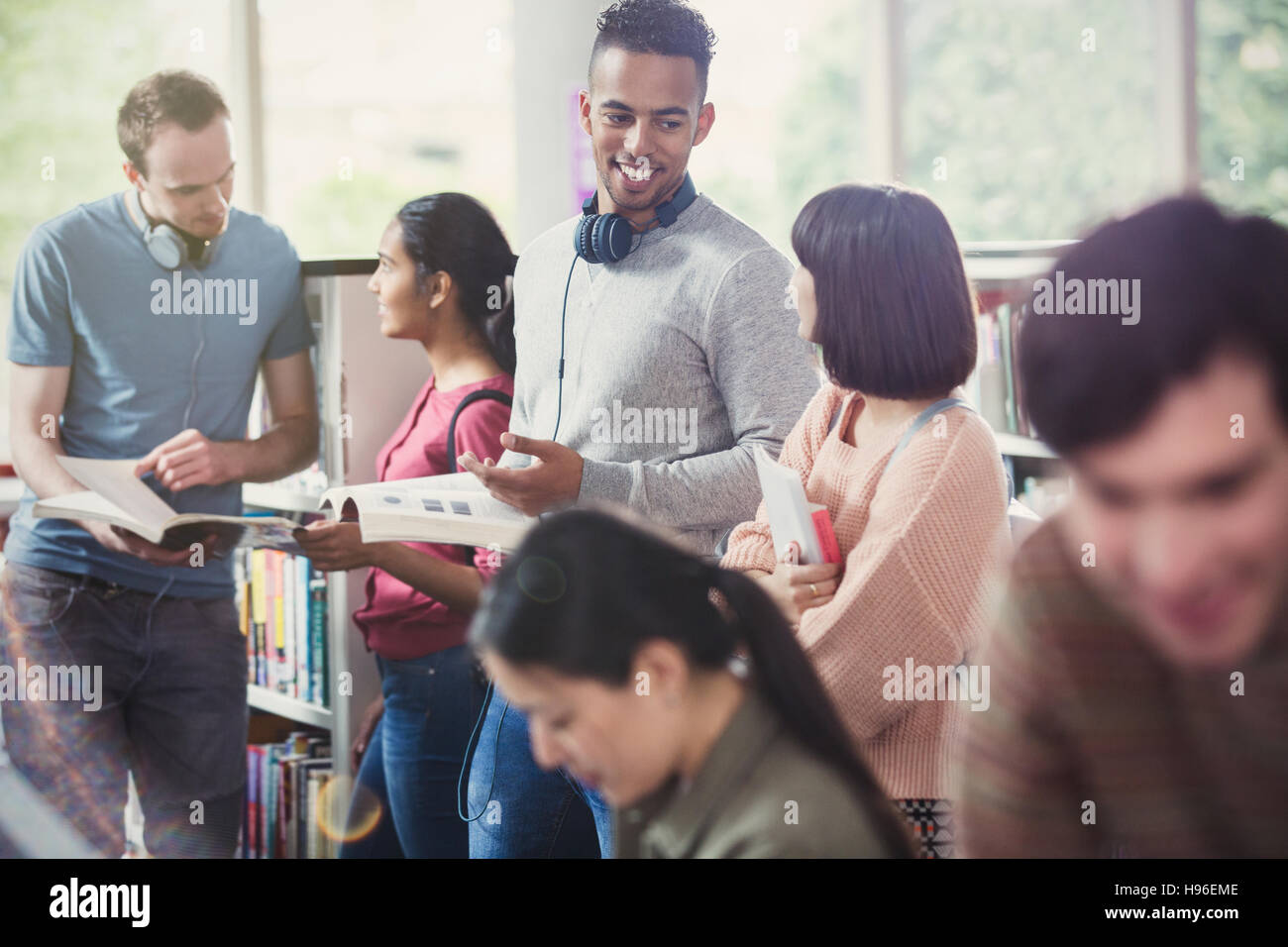 College students talking and studying in library Stock Photo - Alamy