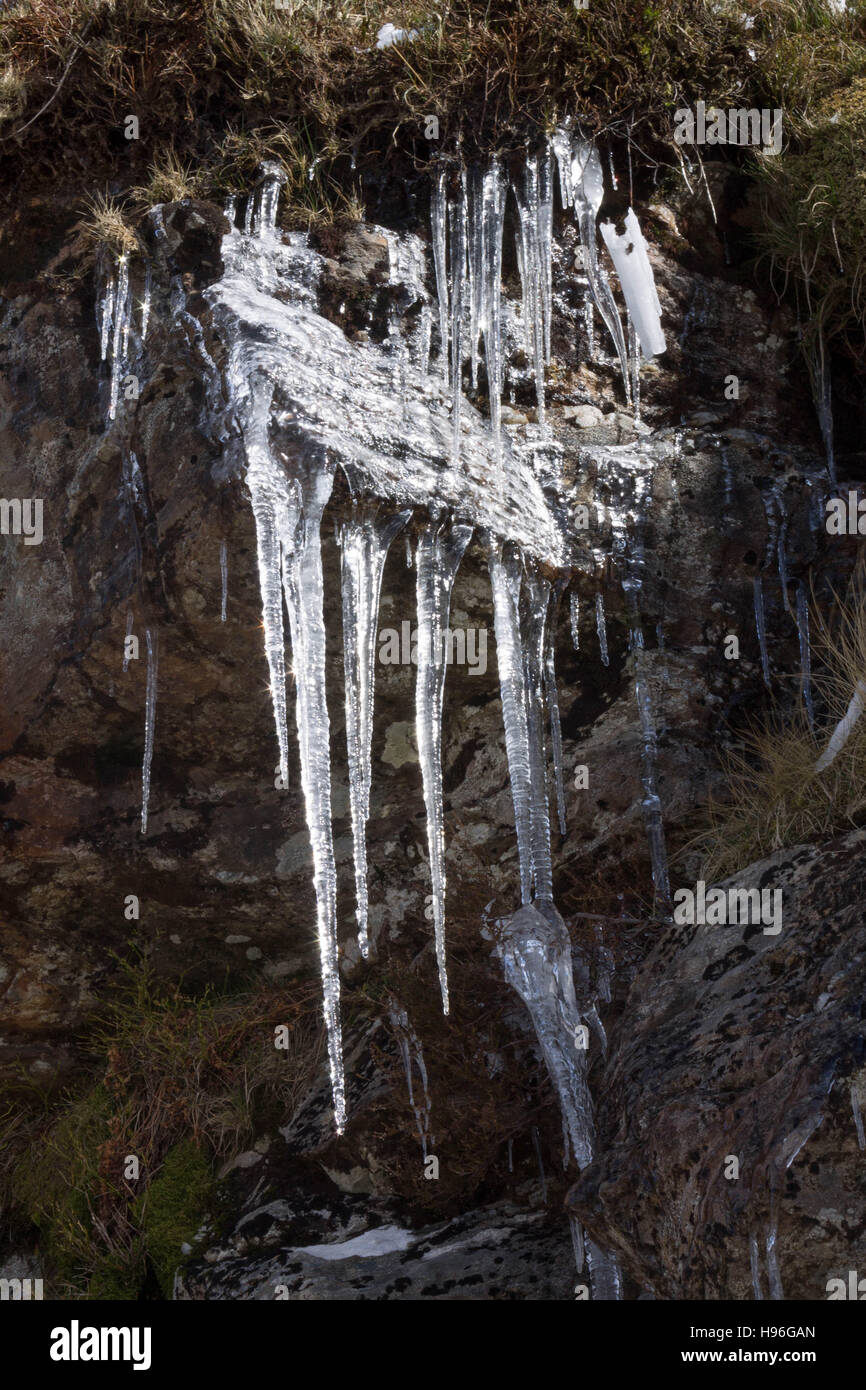 A picture of sun rays shining on icicles hanging off a cliff Stock ...