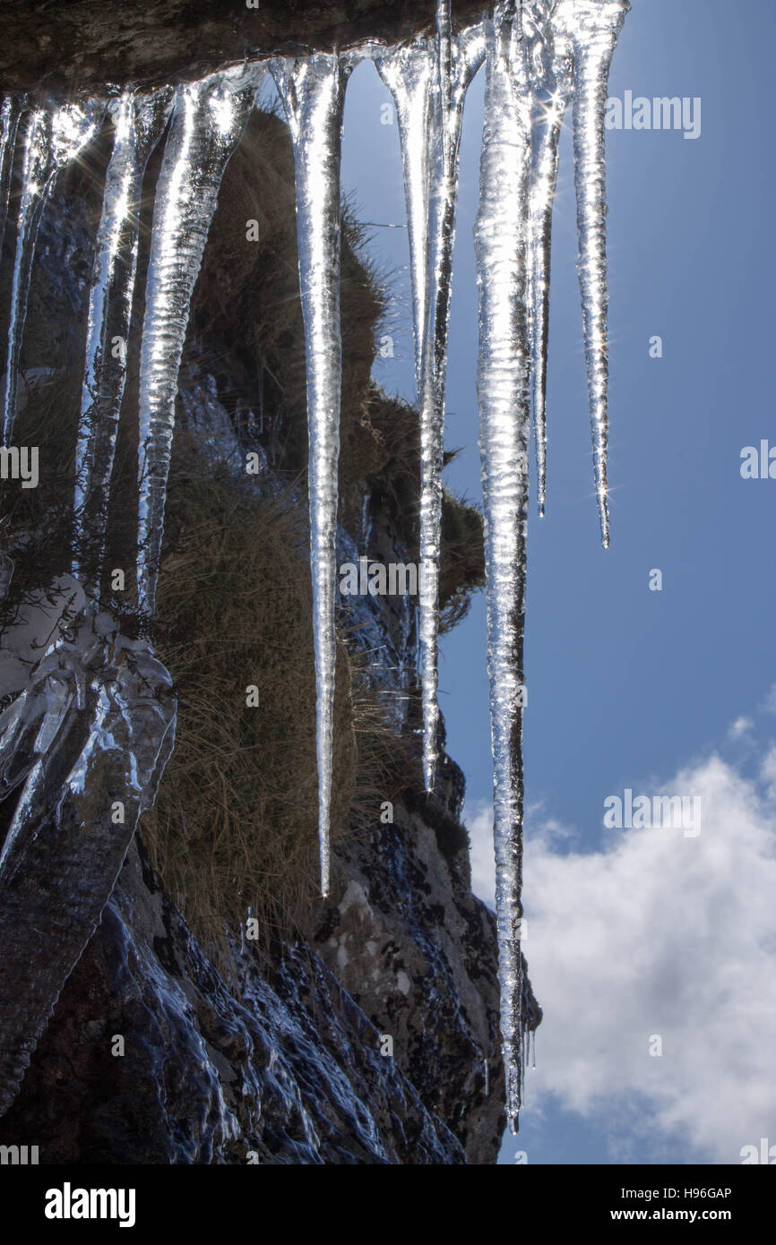 A picture of sun rays shining on icicles hanging off a cliff Stock ...