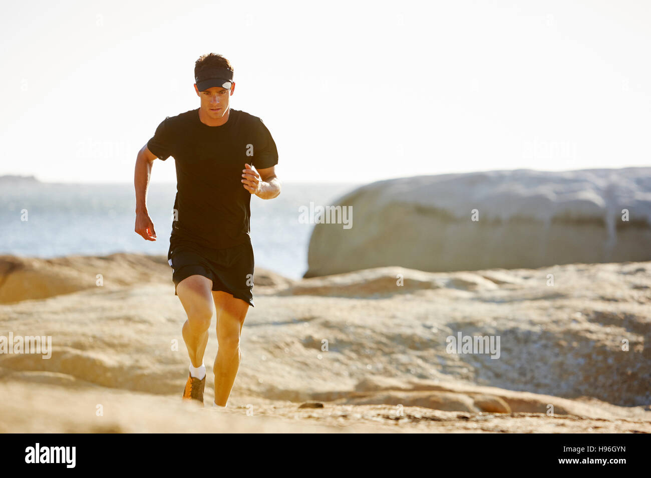 Male triathlete running on sunny rocky trail Stock Photo - Alamy