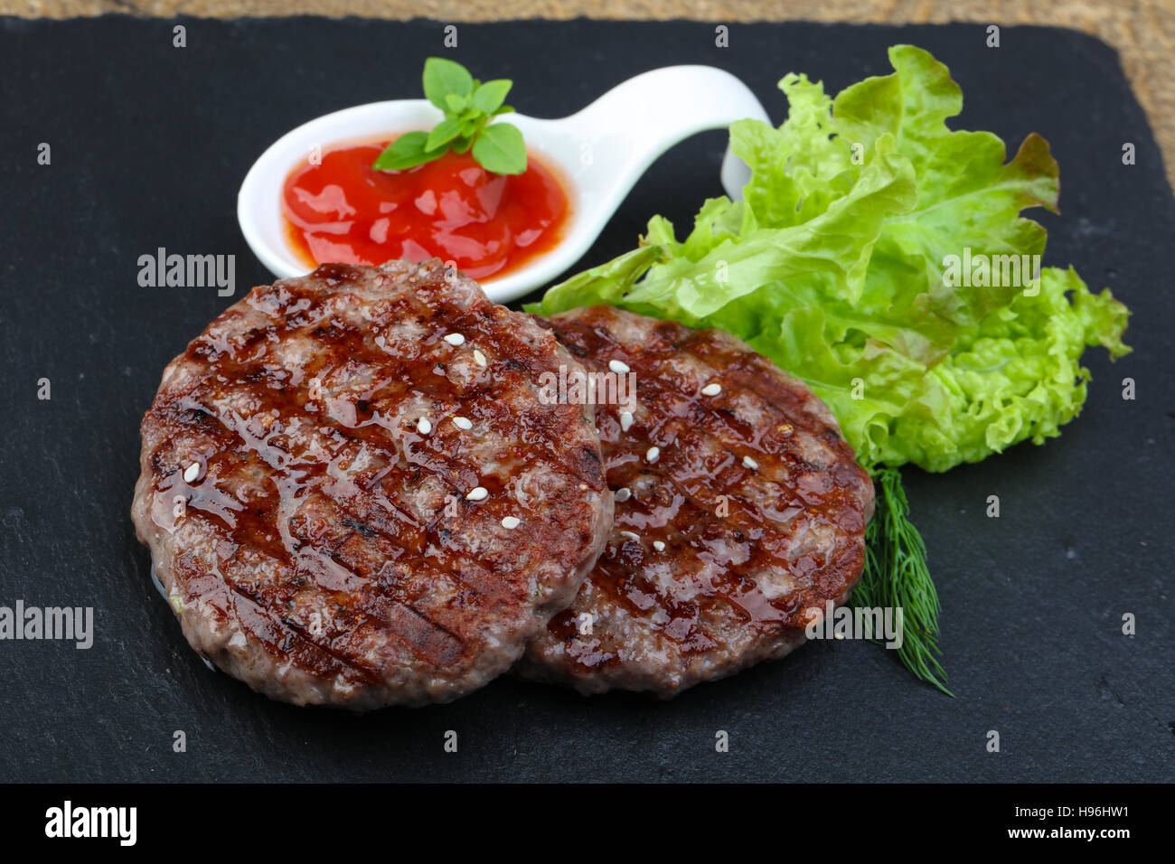 Grilled burger cutlet with onion and salad leaves Stock Photo - Alamy