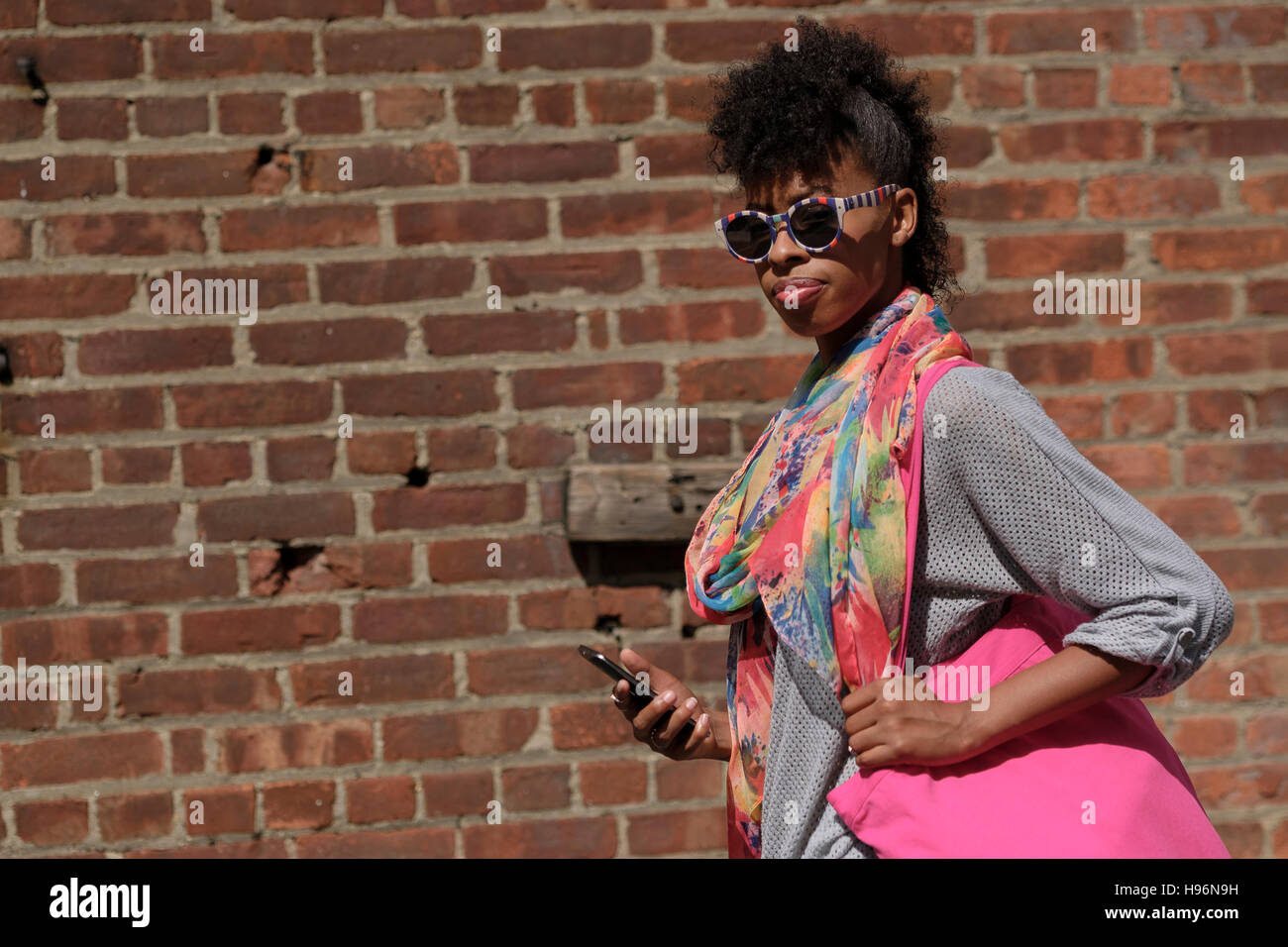 Young woman against brick wall Stock Photo - Alamy