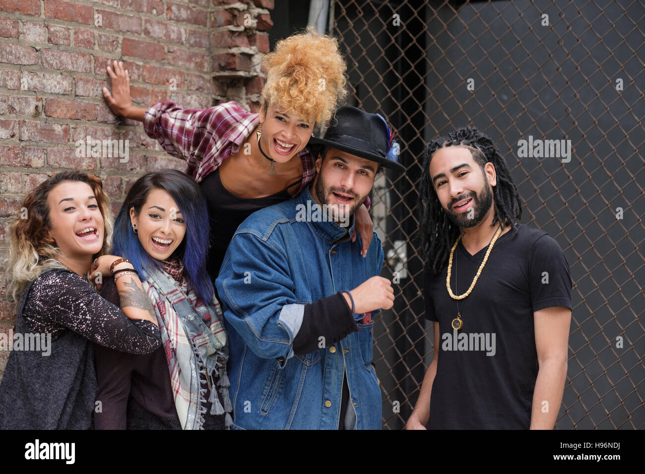 Portrait of happy friends against brick wall Stock Photo - Alamy