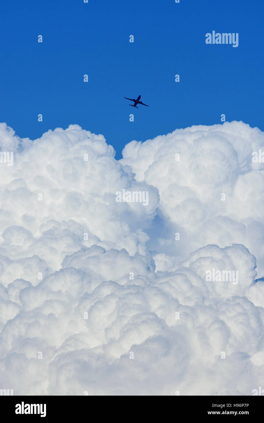 Airplane flying over large cloud Stock Photo - Alamy