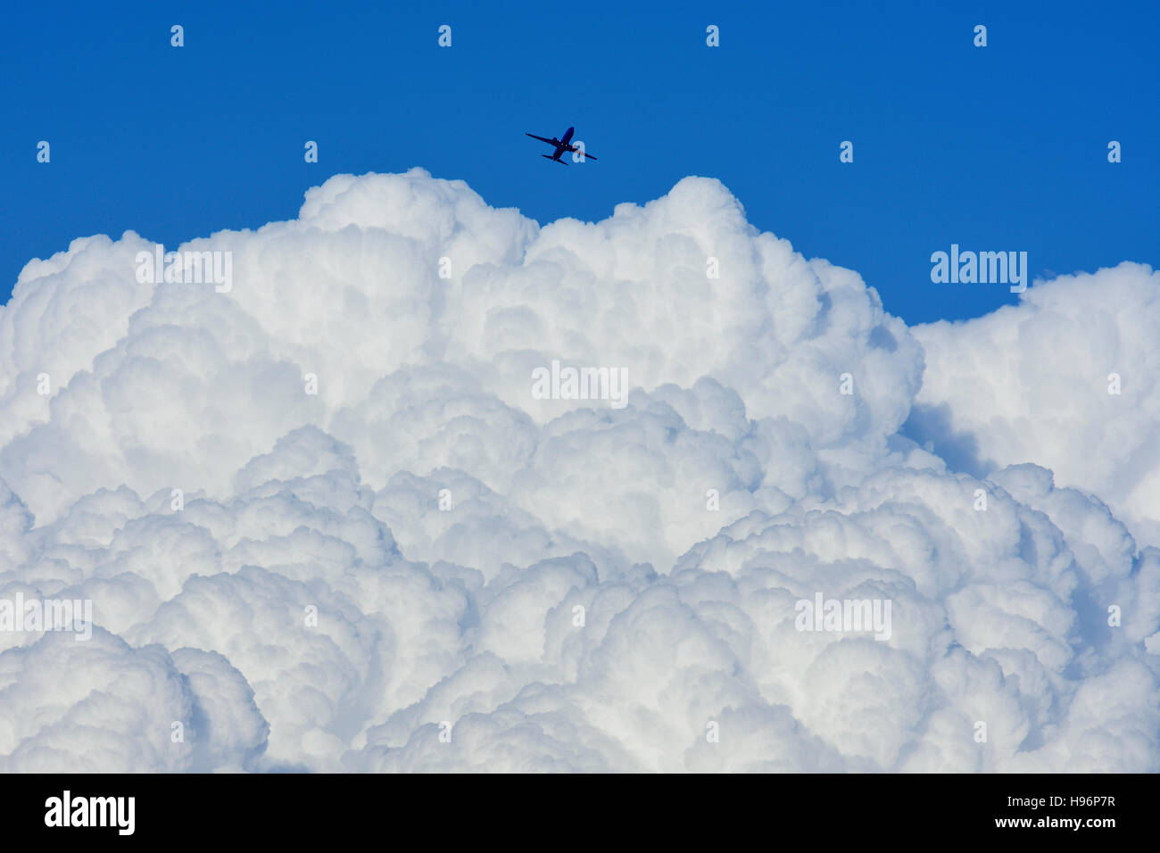 Airplane flying over large cloud Stock Photo - Alamy