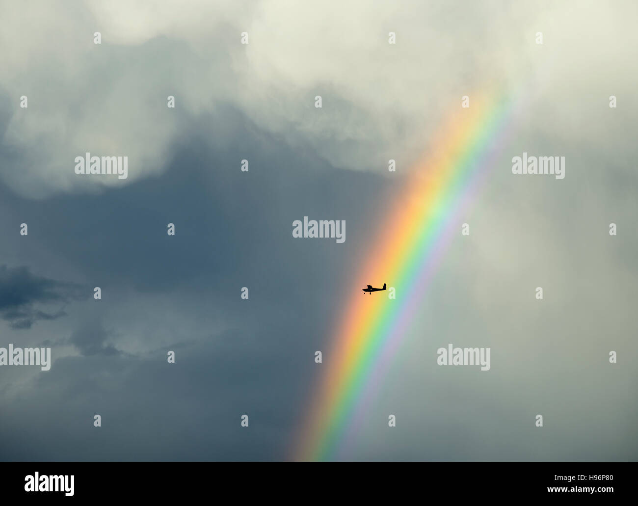 Silhouette of small plane flying through rainbow Stock Photo - Alamy