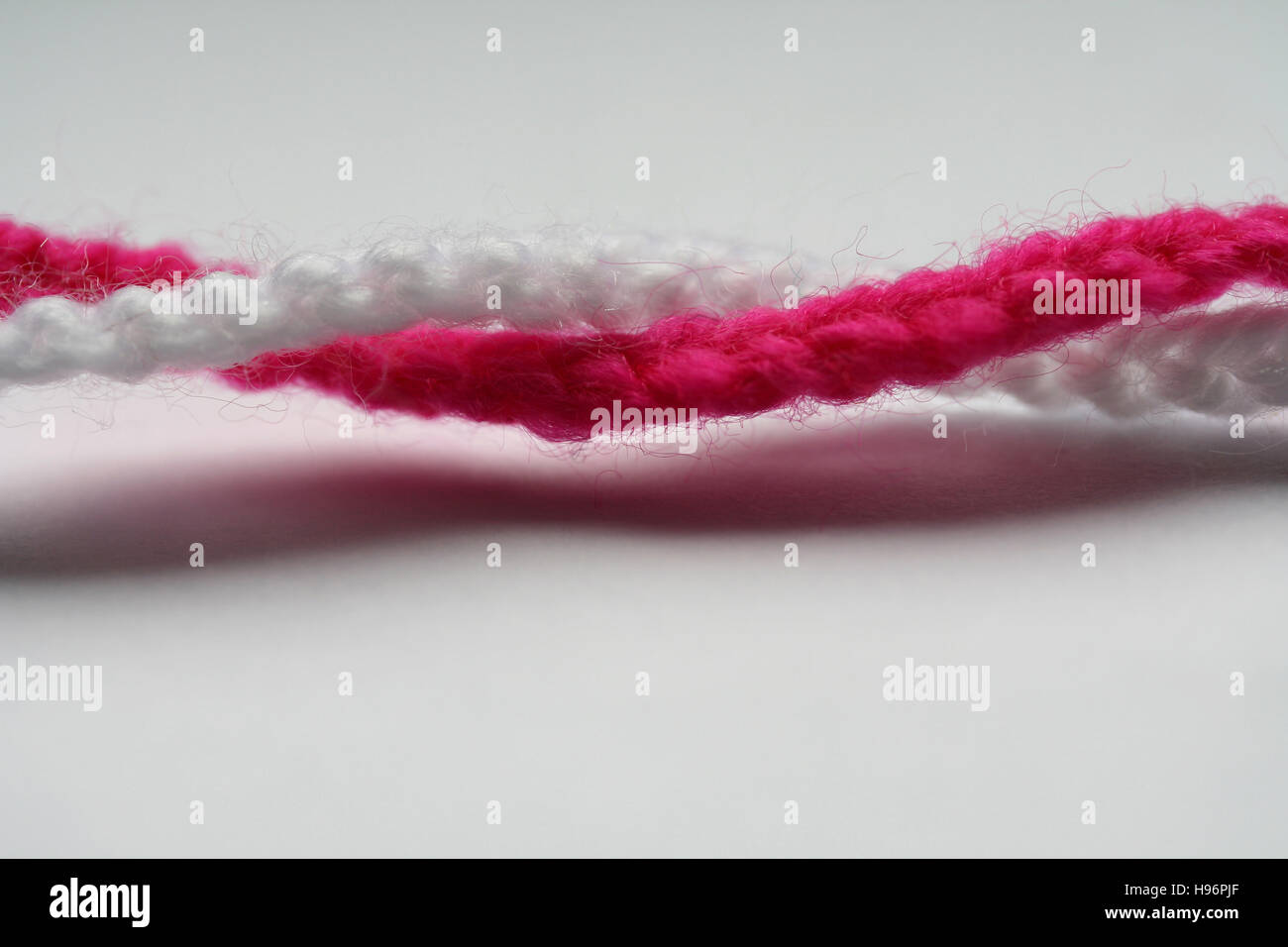 Two braided strands (one pink, one white) twisted together over a white ...