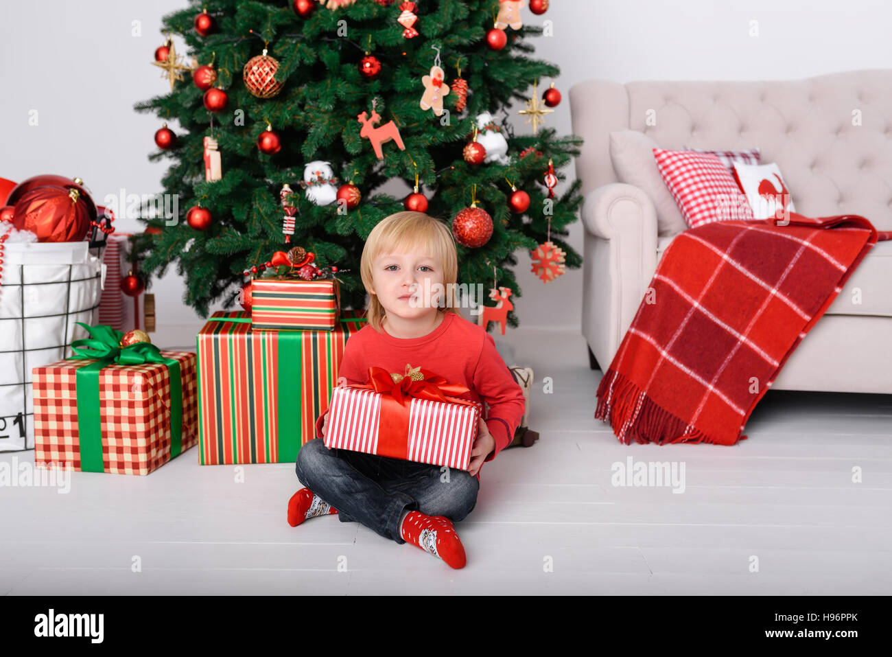 The child with a gift near the Christmas tree Stock Photo - Alamy