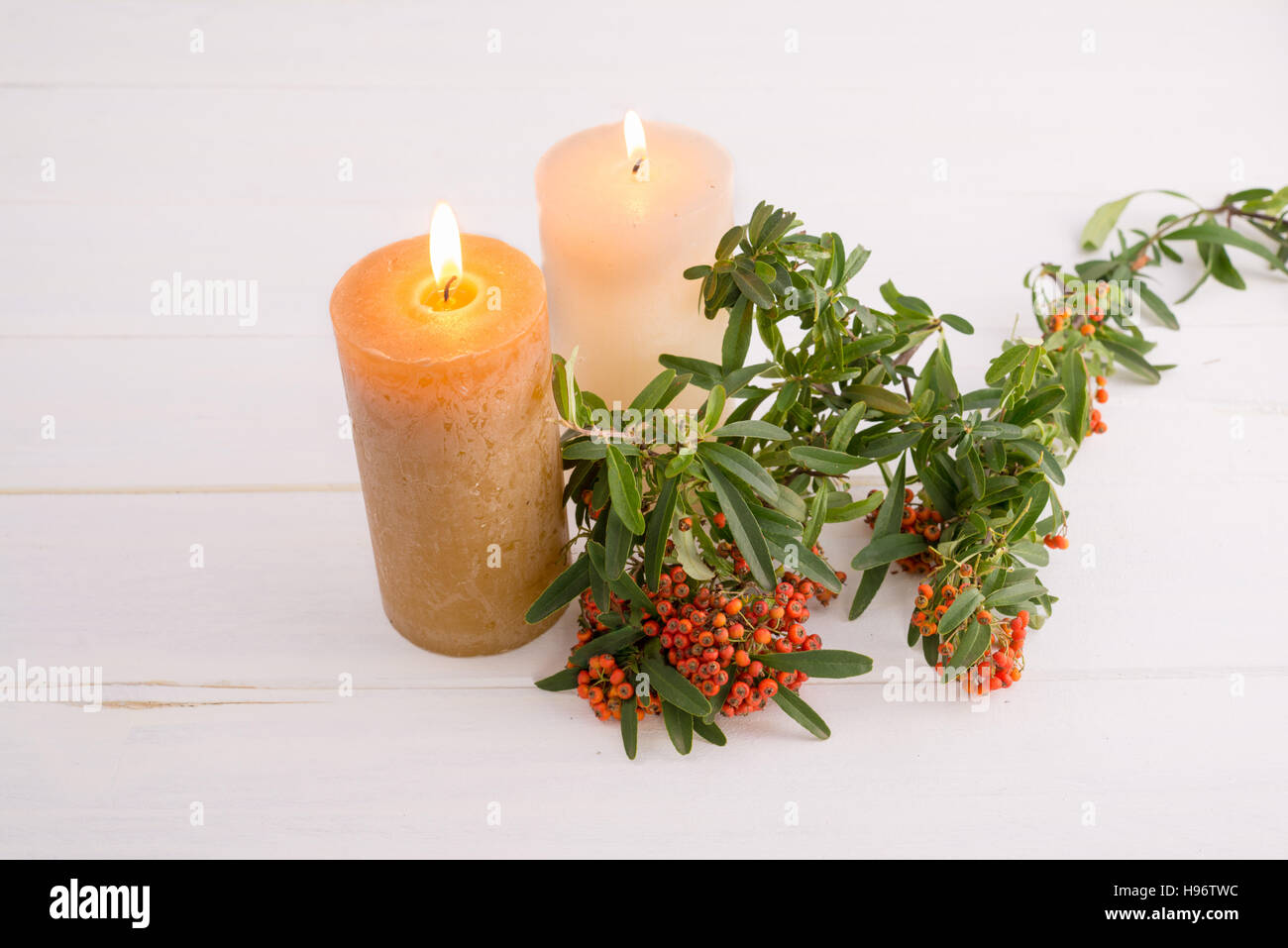 Burning candle and red berries Stock Photo - Alamy