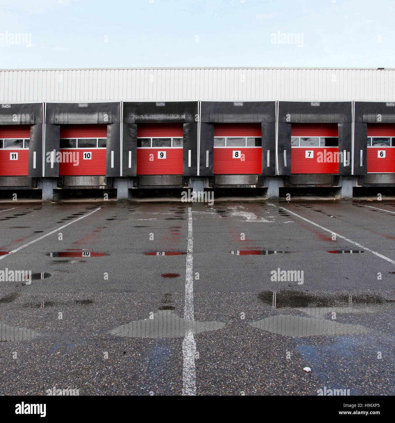numbers 6 to 11 on red doors of loading docks behind rain puddles on ...