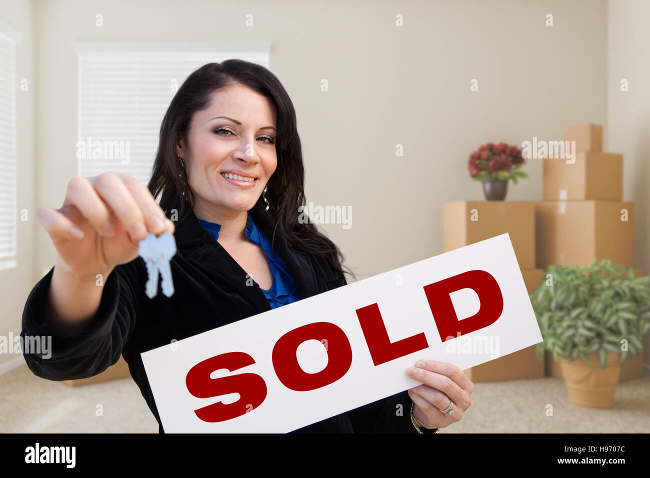 Happy Hispanic Female Real Estate Agent with Sold Sign and Keys in Room ...