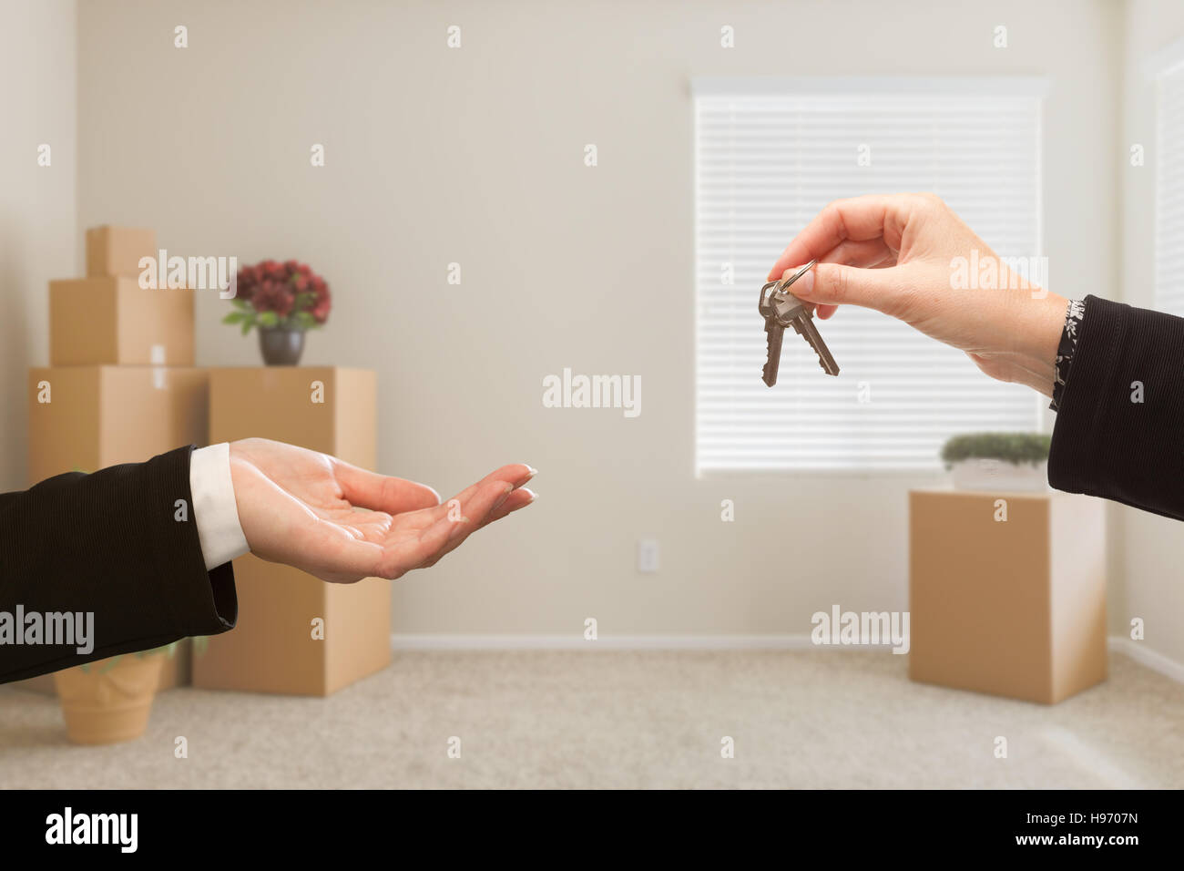 Woman Handing Over House Keys In Room with Packed Moving Boxes Stock ...