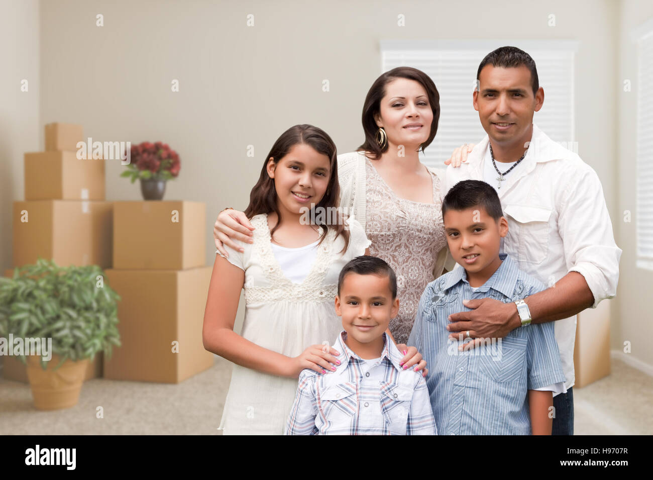 Happy Hispanic Family in Empty Room with Packed Moving Boxes and Potted ...