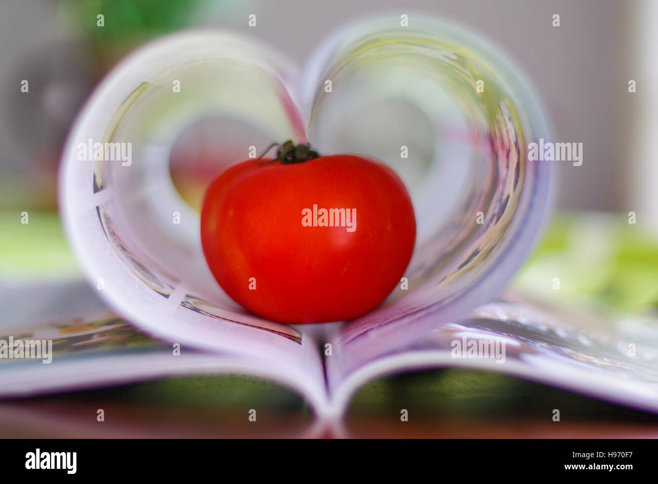 Red rope tomato between the pages of a magazine in the form of heart ...