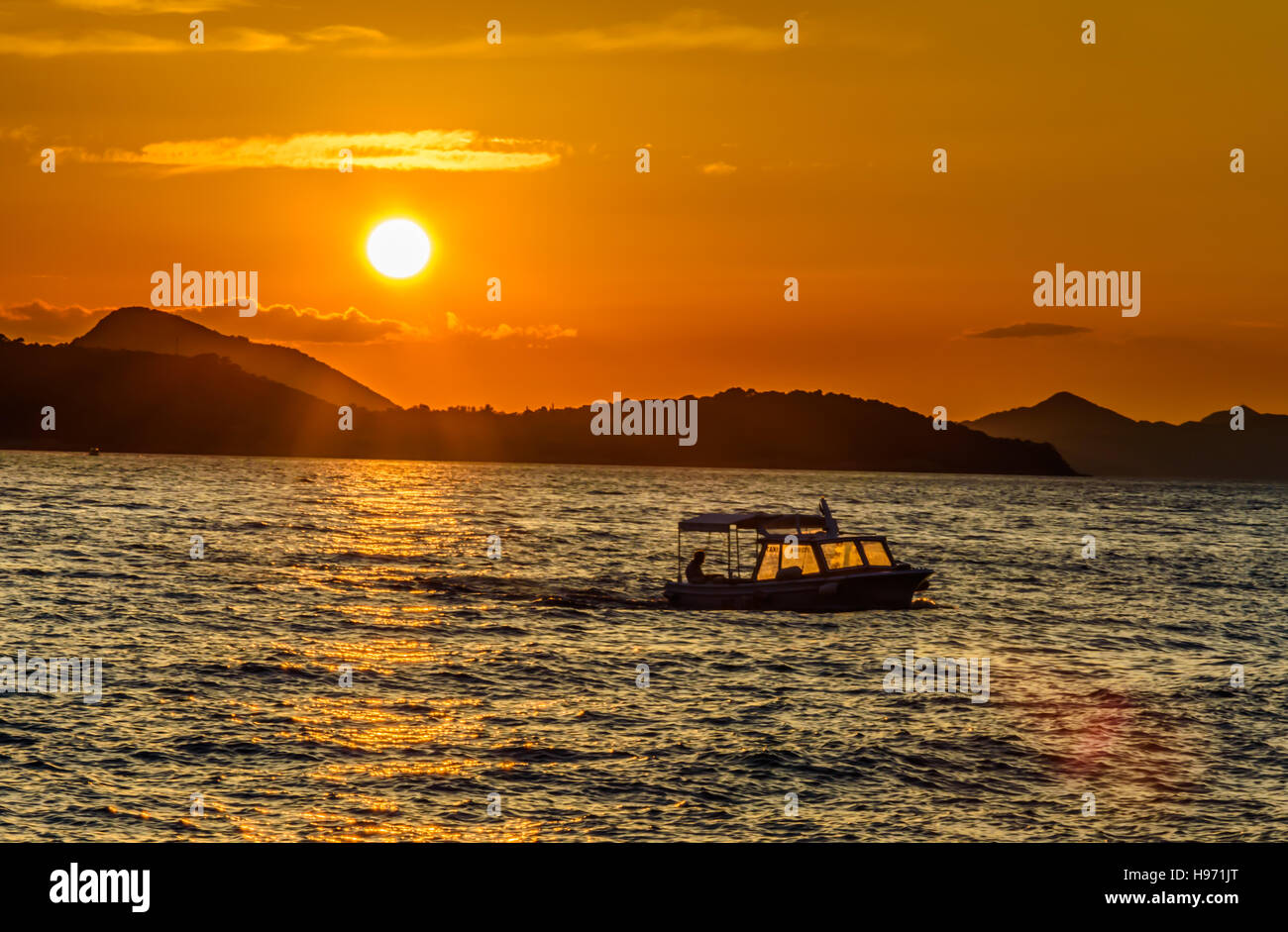 Boat sailing at sunset Stock Photo - Alamy