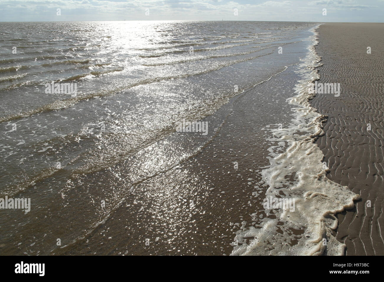Sun shining on rising tide channel River Ribble washing line of sea ...