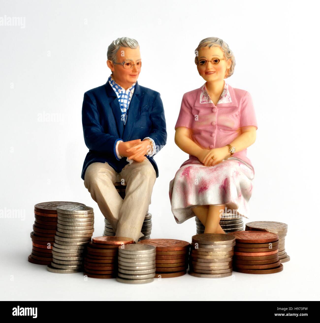 A miniature figurine senior elderly couple sitting amongst some coins ...