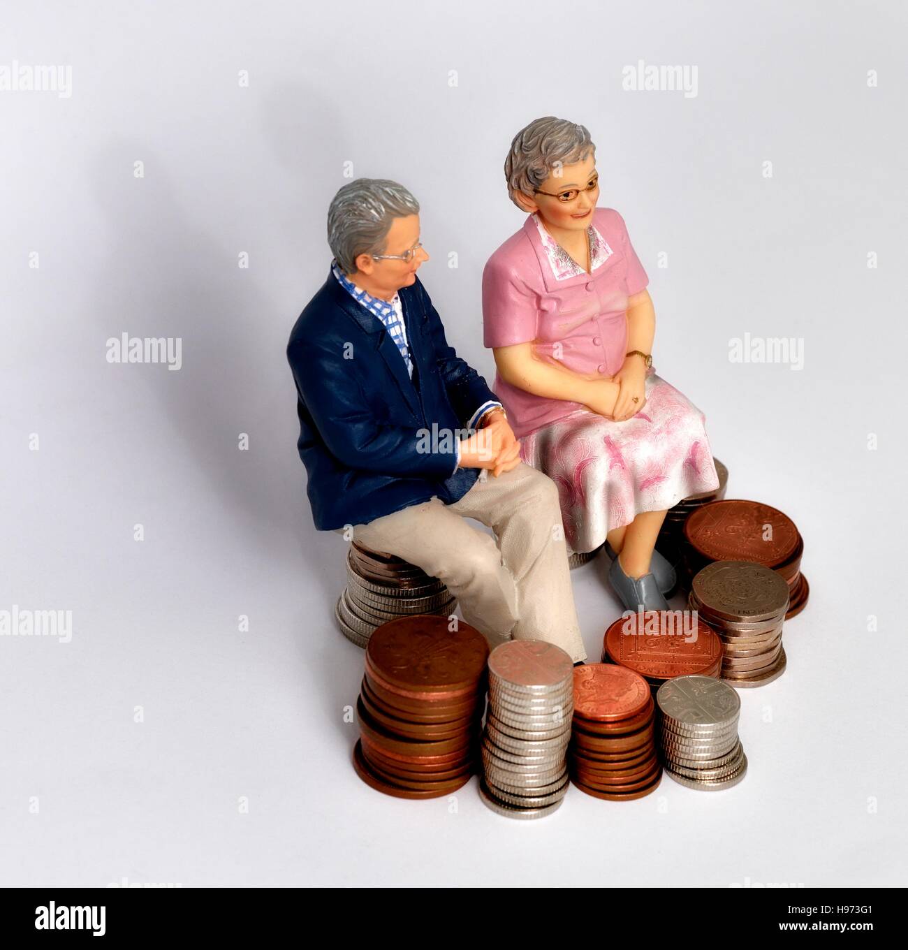 A miniature figurine senior elderly couple sitting amongst some coins ...