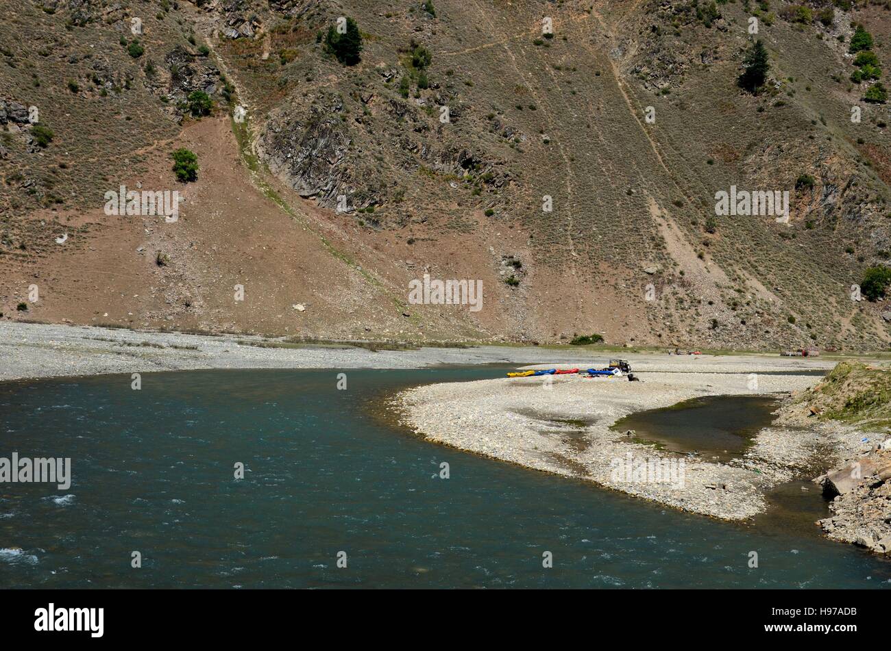 Colorful white water rafts vessels rest on the shore of Kunhar River ...