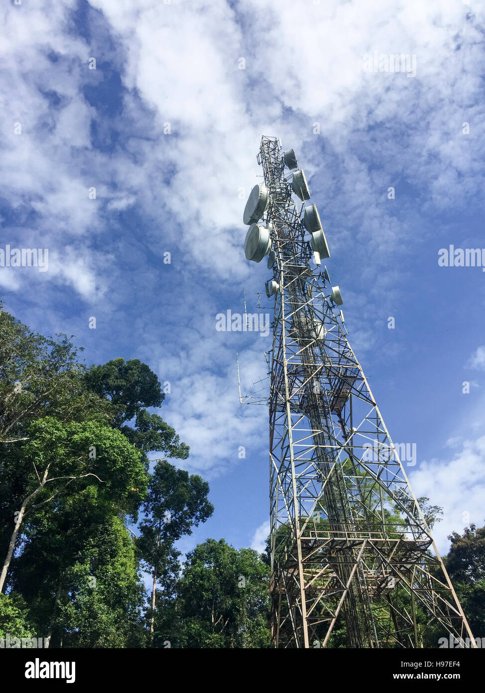 Common communication tower, cellphone tower against blue sky and clouds ...