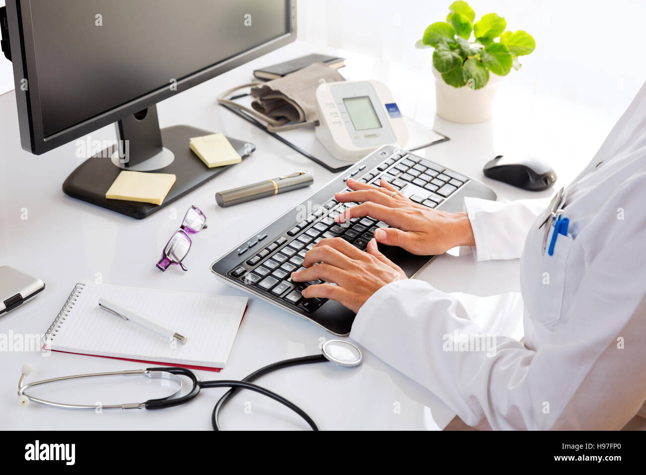 Female doctor typing on desktop computer, inside her office Stock Photo ...