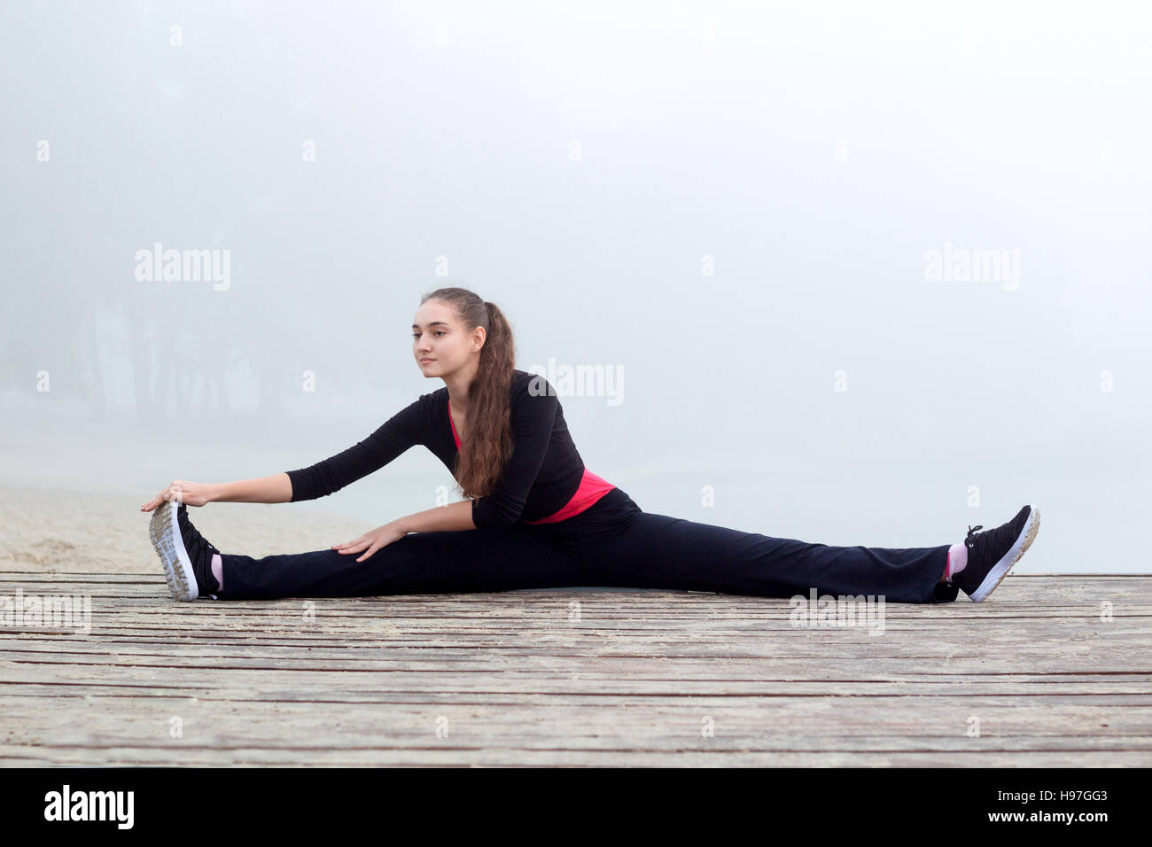 Young pretty slim fitness sporty woman does stretching exercises during ...