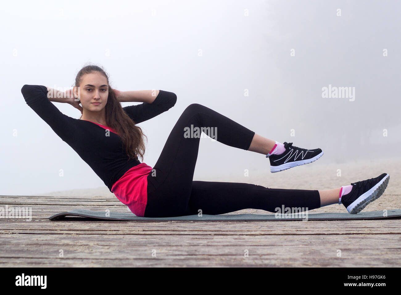Young pretty slim fitness sporty woman does abs exercises during ...