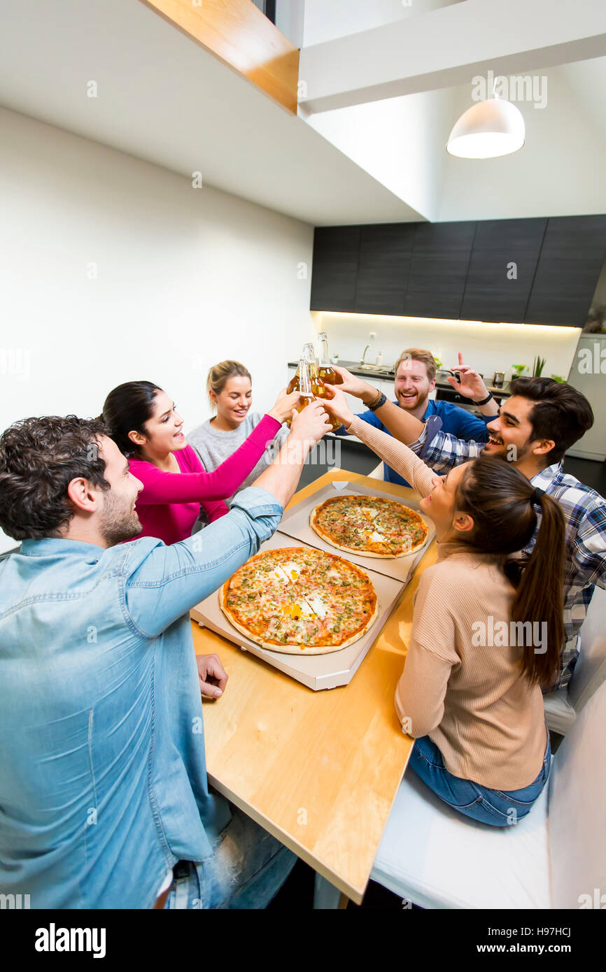 Group of happy young people eating pizza and drinking cider in the ...