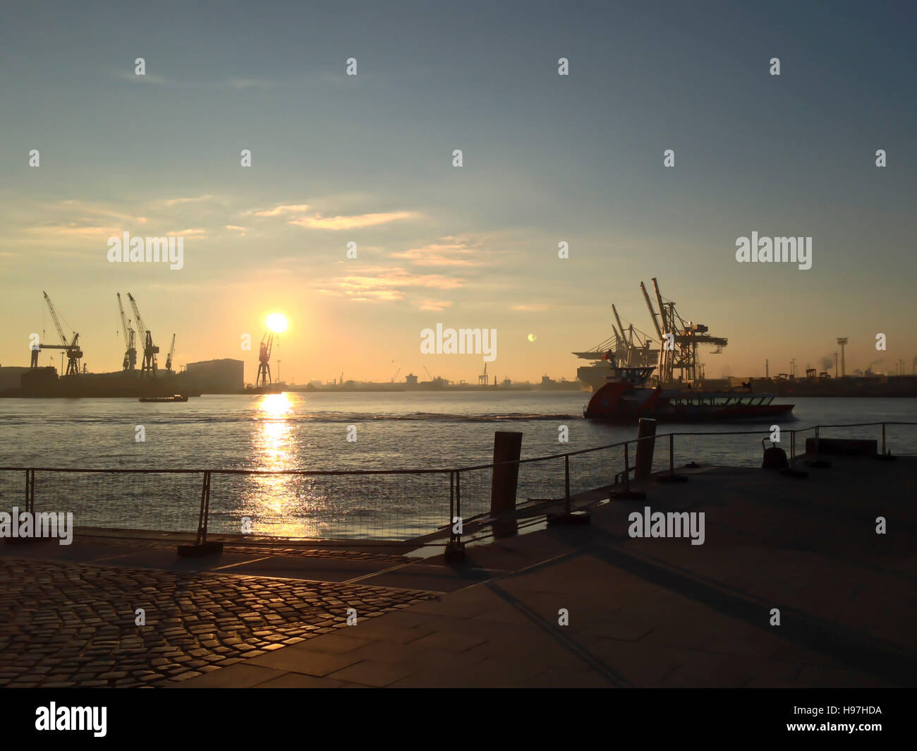 Sunset over a harbour and docks with the sun reflecting across the ...