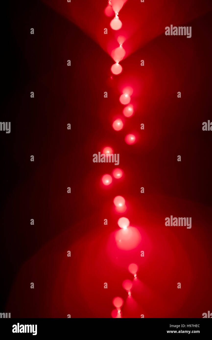 Polygonal red colored light beams in center of solid black background ...