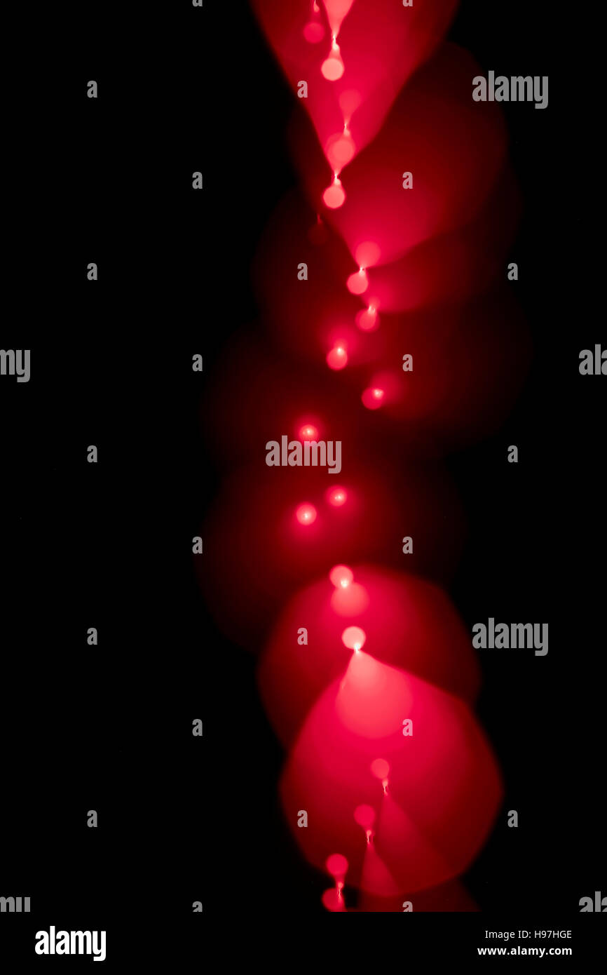 Polygonal red colored light beams in center of solid black background ...