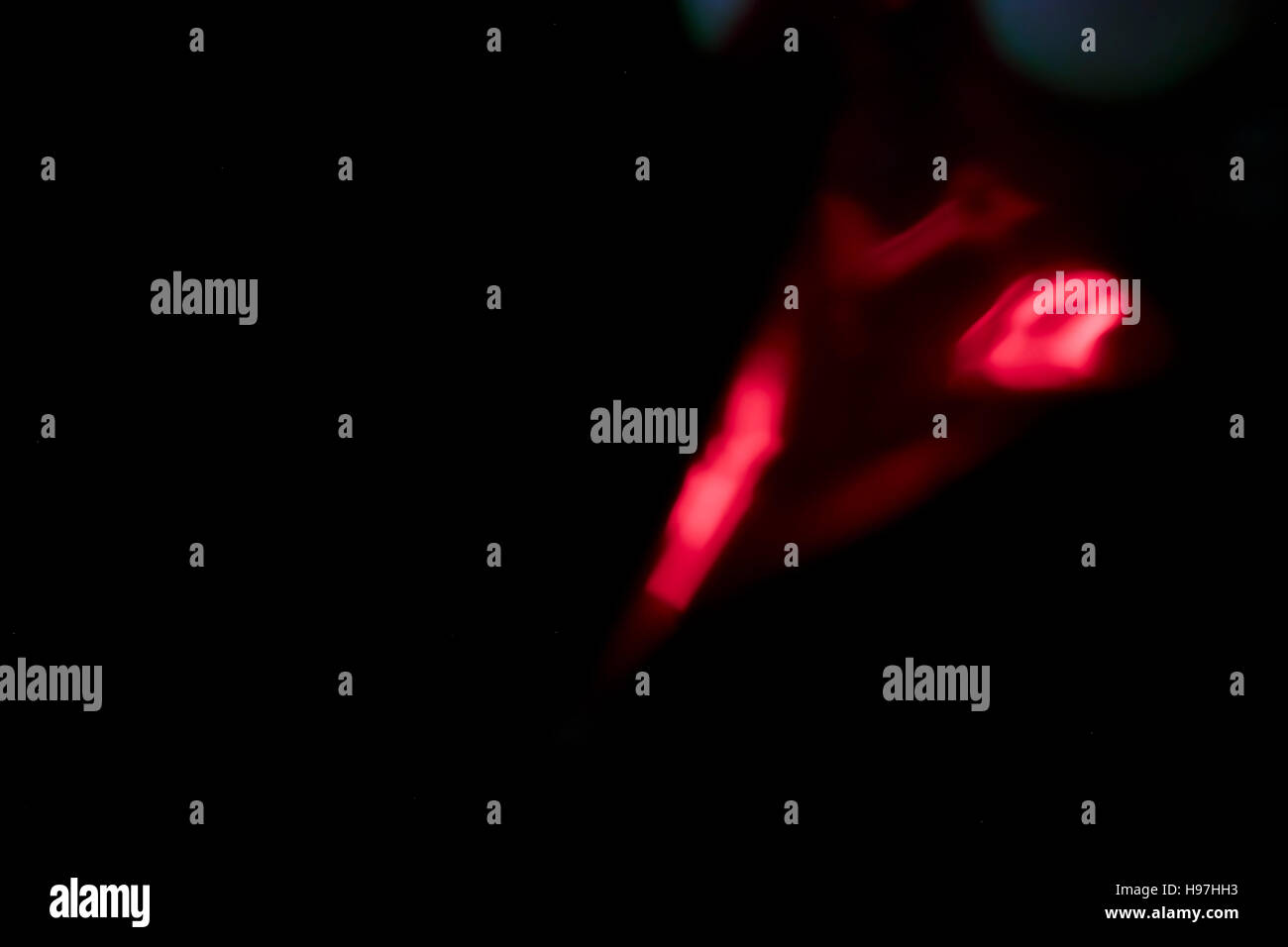 Polygonal red colored light beams in center of solid black background ...