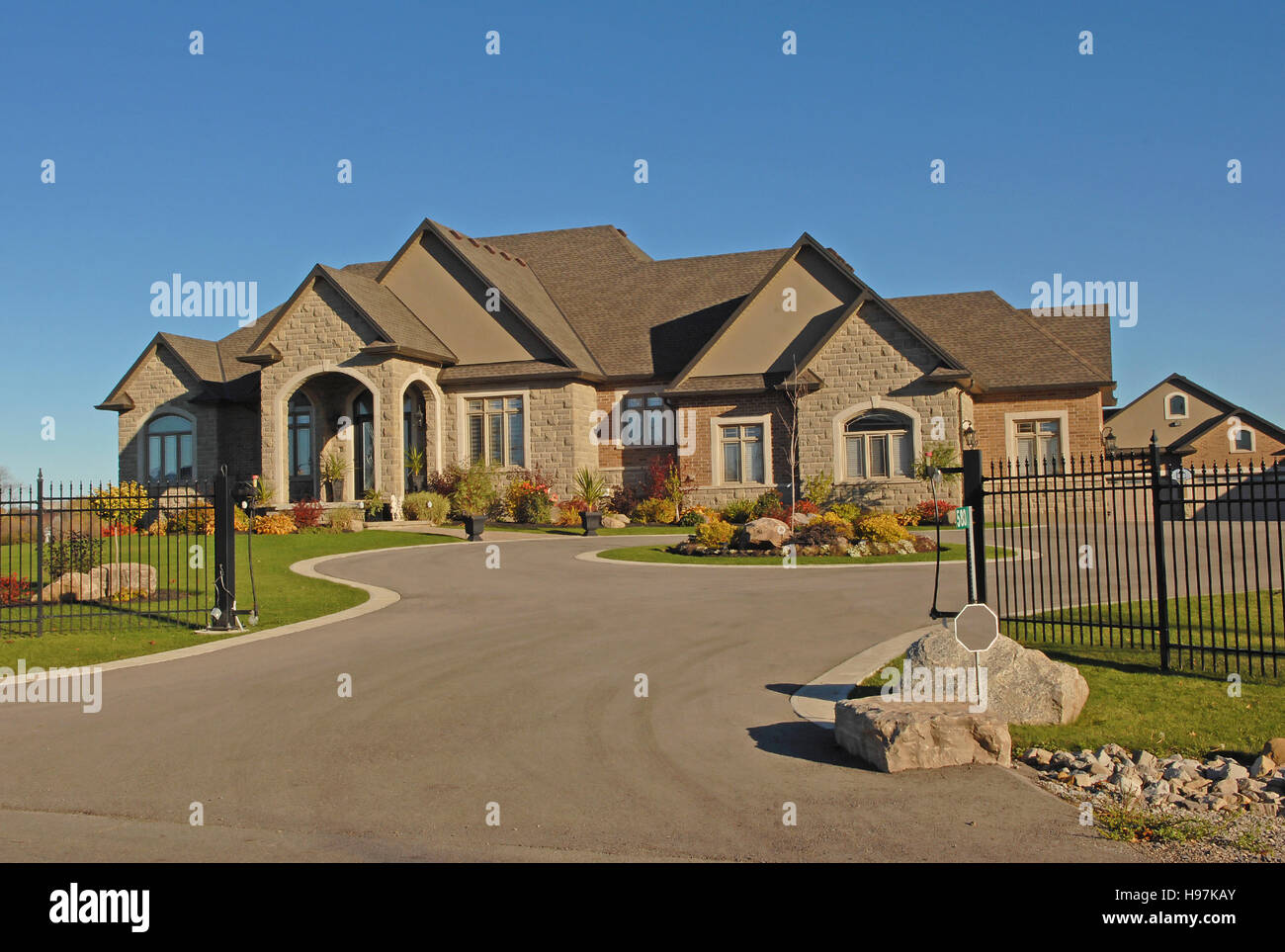 The front few of a new large mansion on a gig lot and driveway with a ...